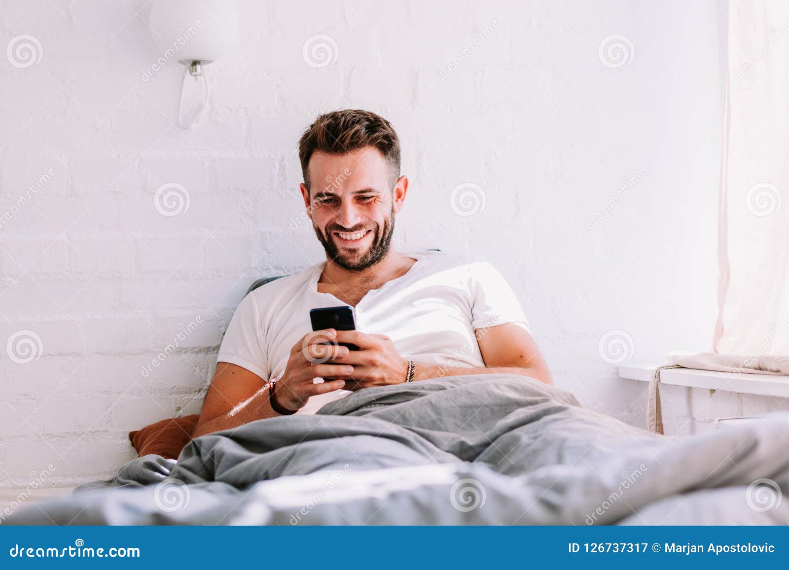 Young Man Using Smartphone in the Bed Stock Image - Image of handsome ...