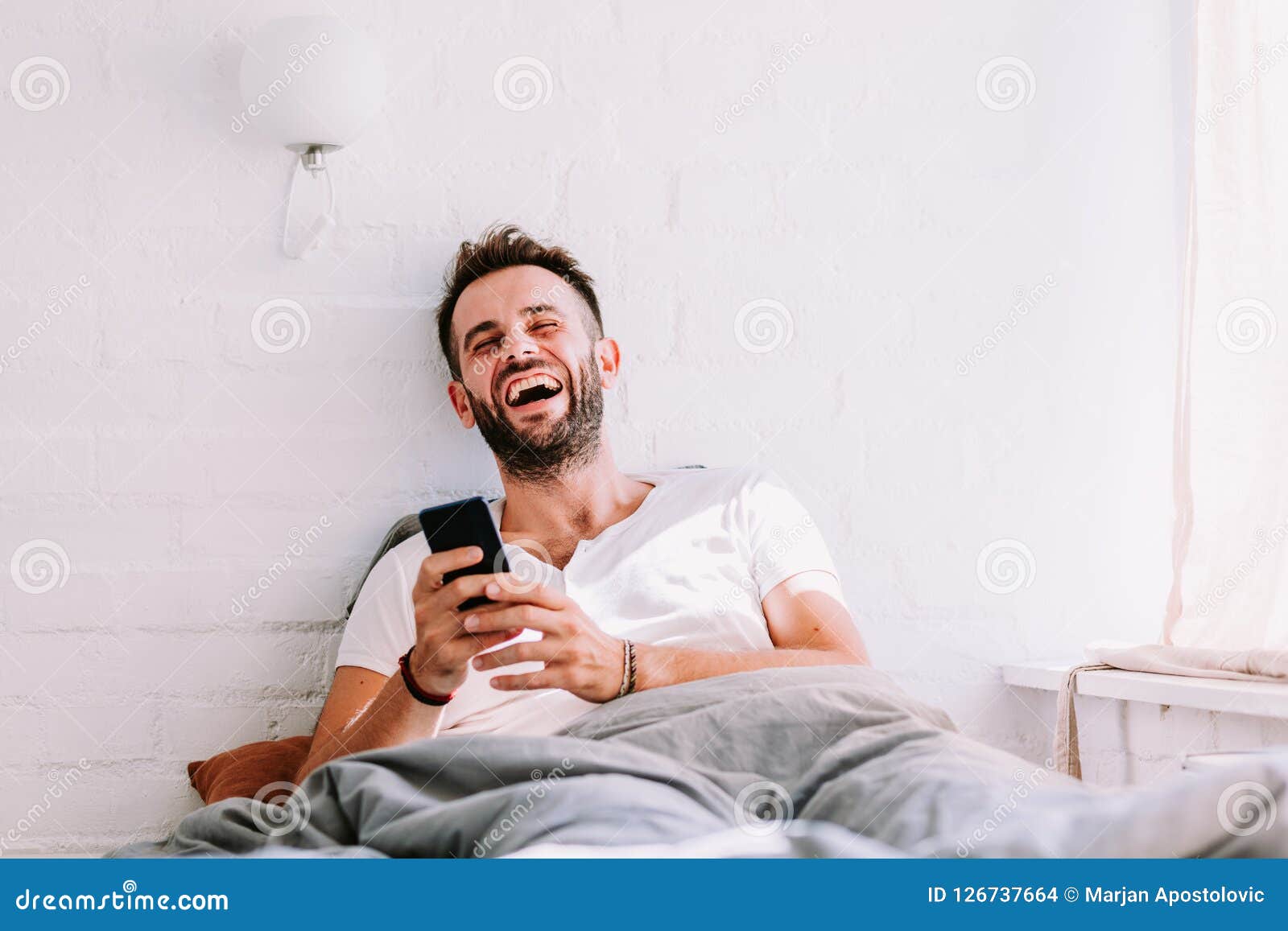 Young Man Using Smartphone in the Bed Stock Photo - Image of male ...