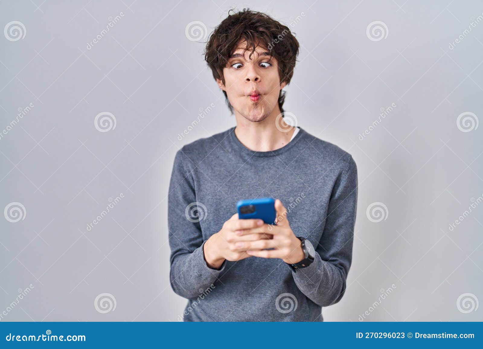 Young Man Using Smartphone Typing a Message Making Fish Face with Mouth ...