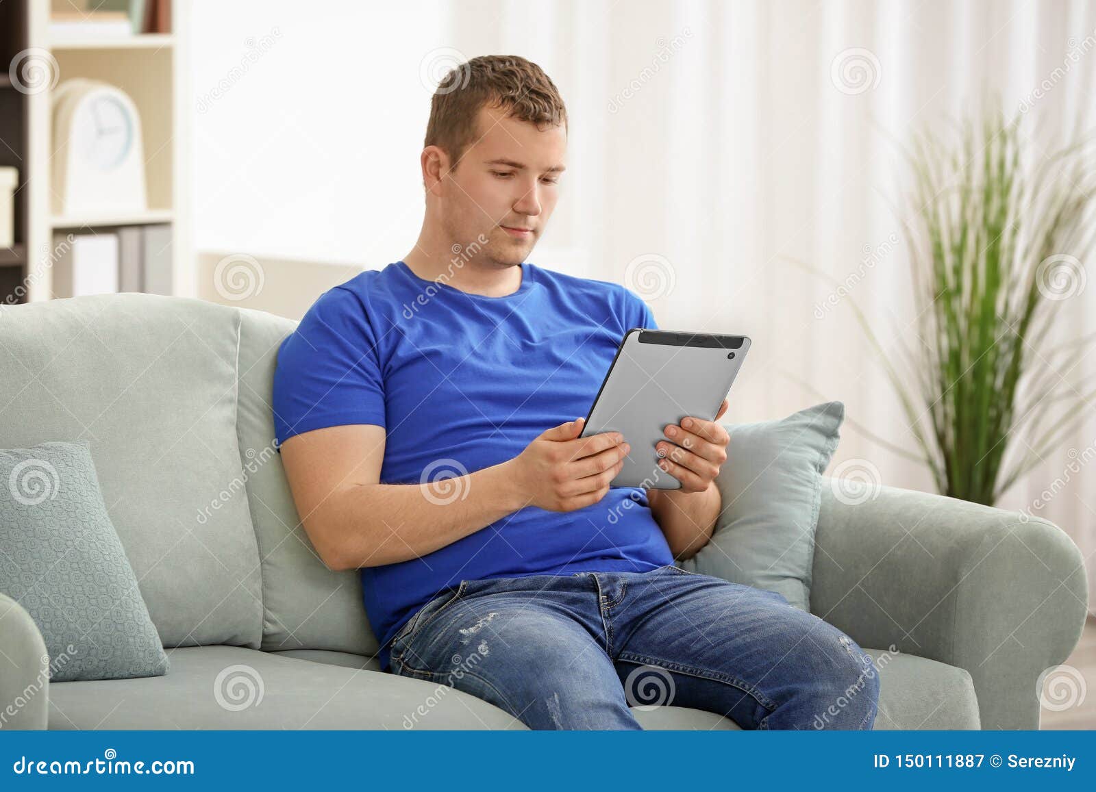 Young Man Using Tablet PC while Resting on Sofa at Home Stock Image ... Young Man Using Tablet PC while Resting on Sofa at Home Stock Image ...