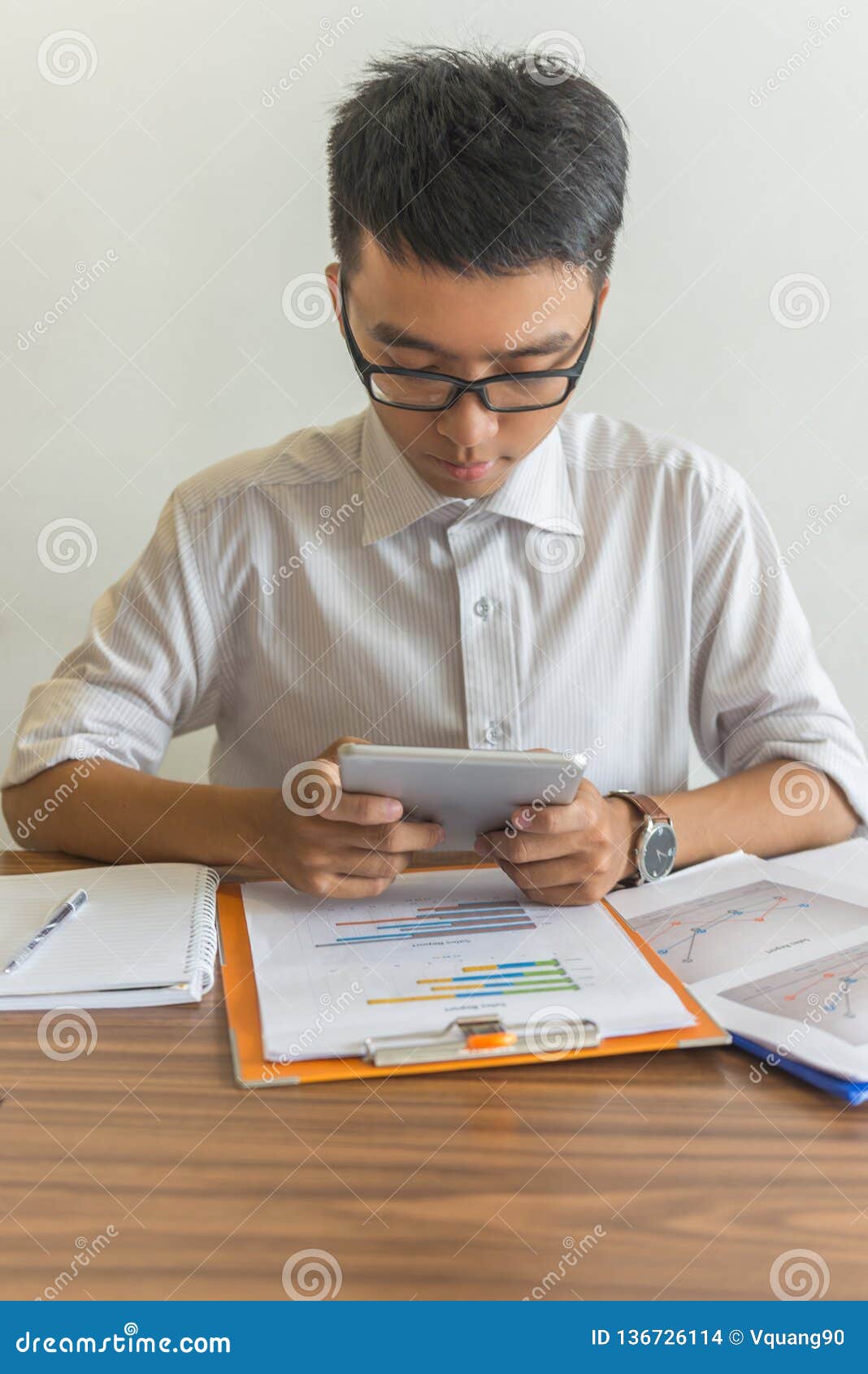 Young Man Using Tablet and Reading Financial Report Stock Photo - Image ...