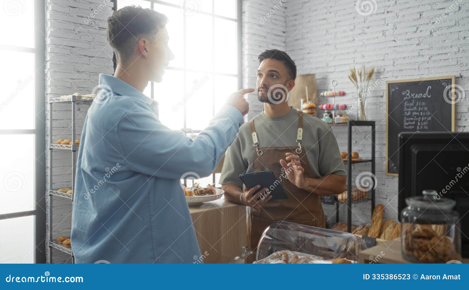 Young Man Using Tablet while Talking with Male Customer in Modern ...