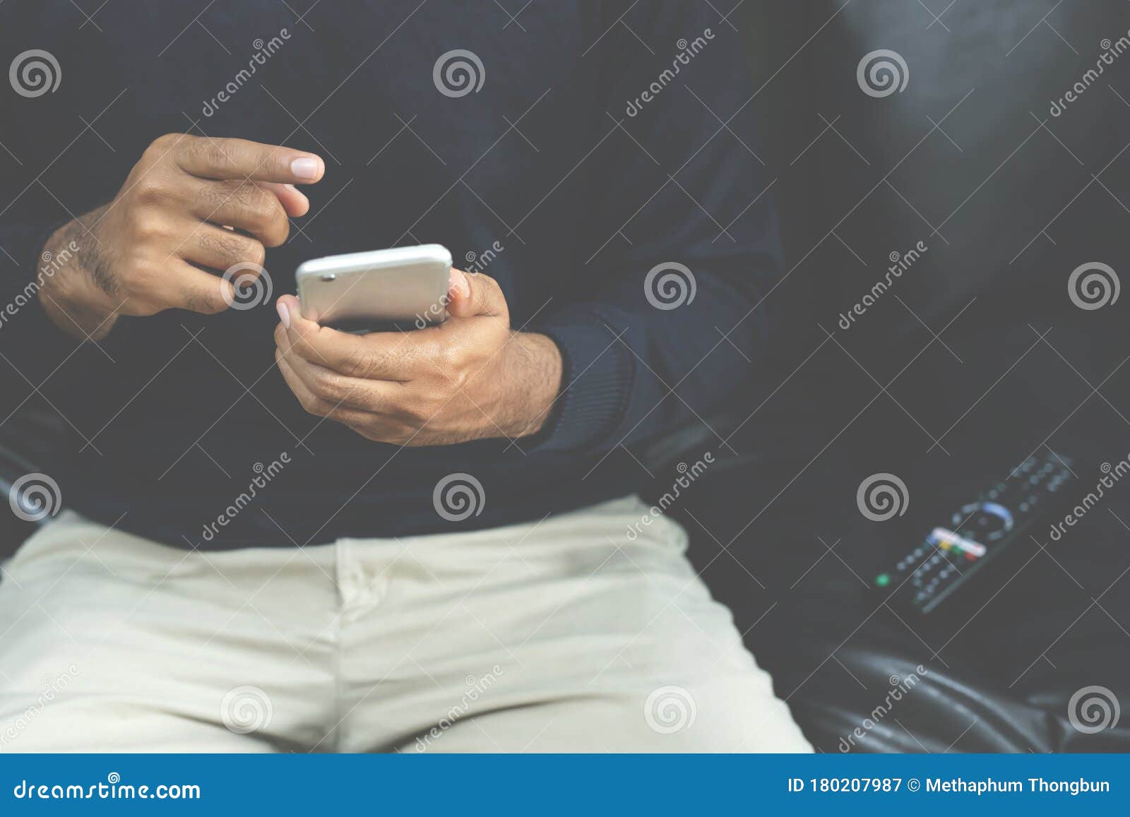 Young Man Using Television Remote Control and Mobile Smart Phone Stock ...