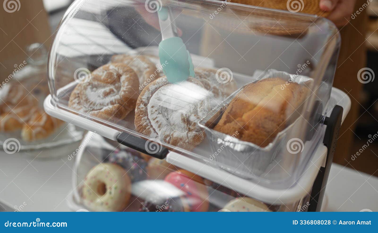 Young Man Using Tongs To Select Pastries from a Display Case in a ...