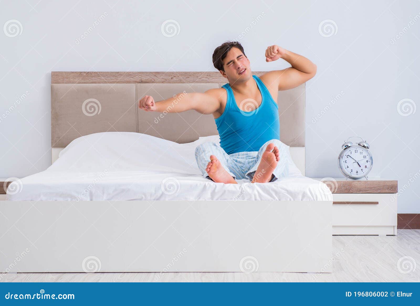 Young man waking up in bed stock photo. Image of apartment - 196806002