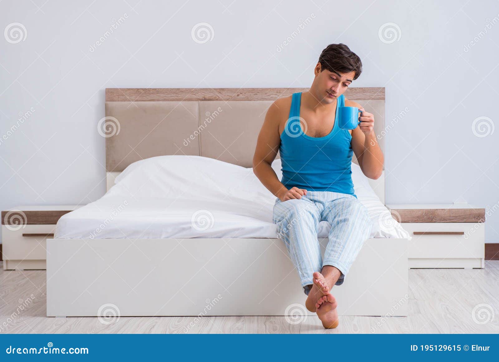Young man waking up in bed stock image. Image of holding - 195129615