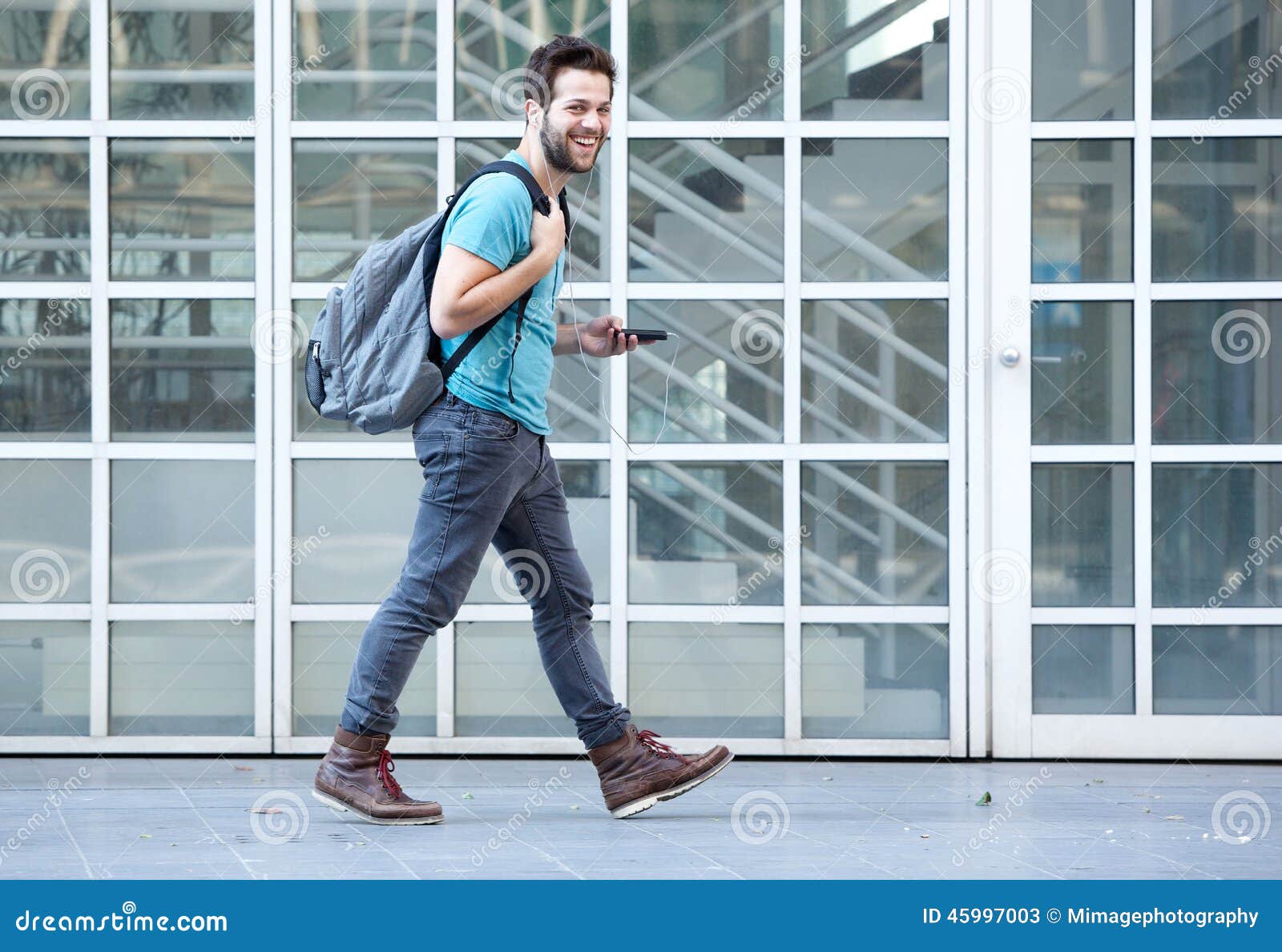 Young Man Walking on Sidewalk with Mobile Phone and Bag Stock Image ...