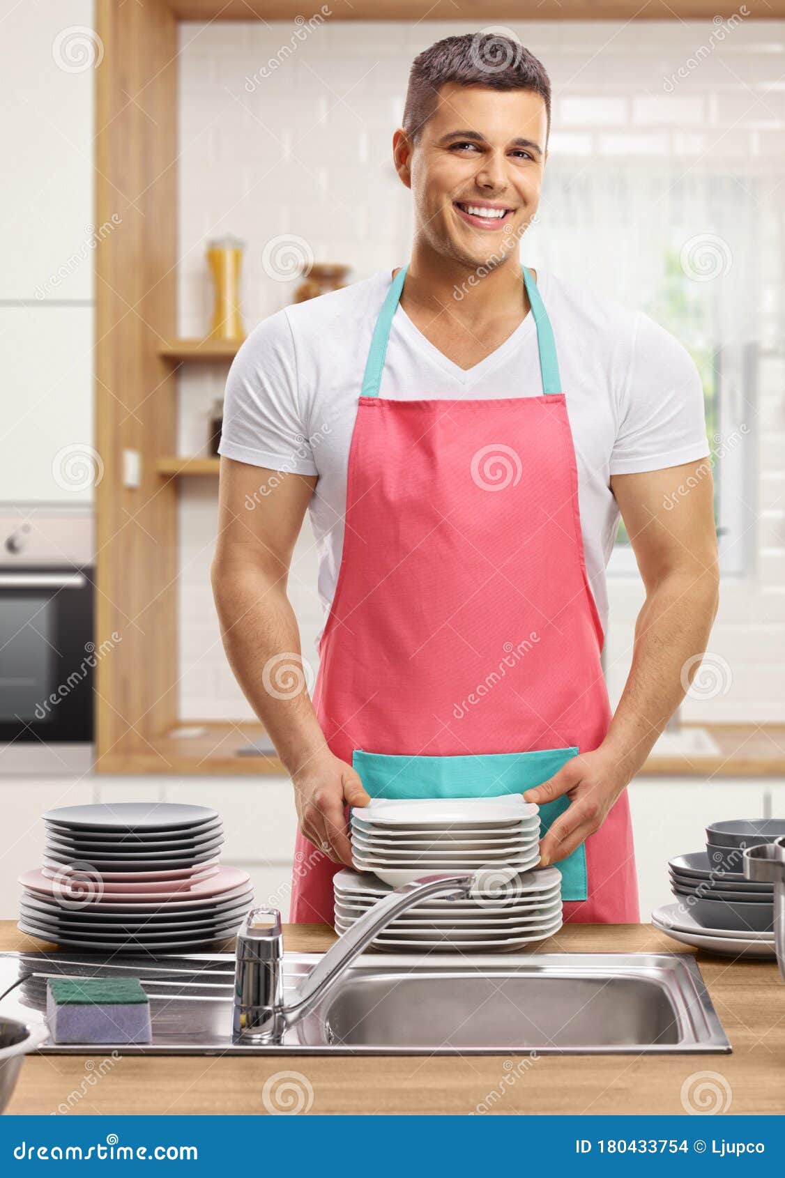 Young Man Wearing Apron and Washing Dishes in a Kitchen Stock Photo ...