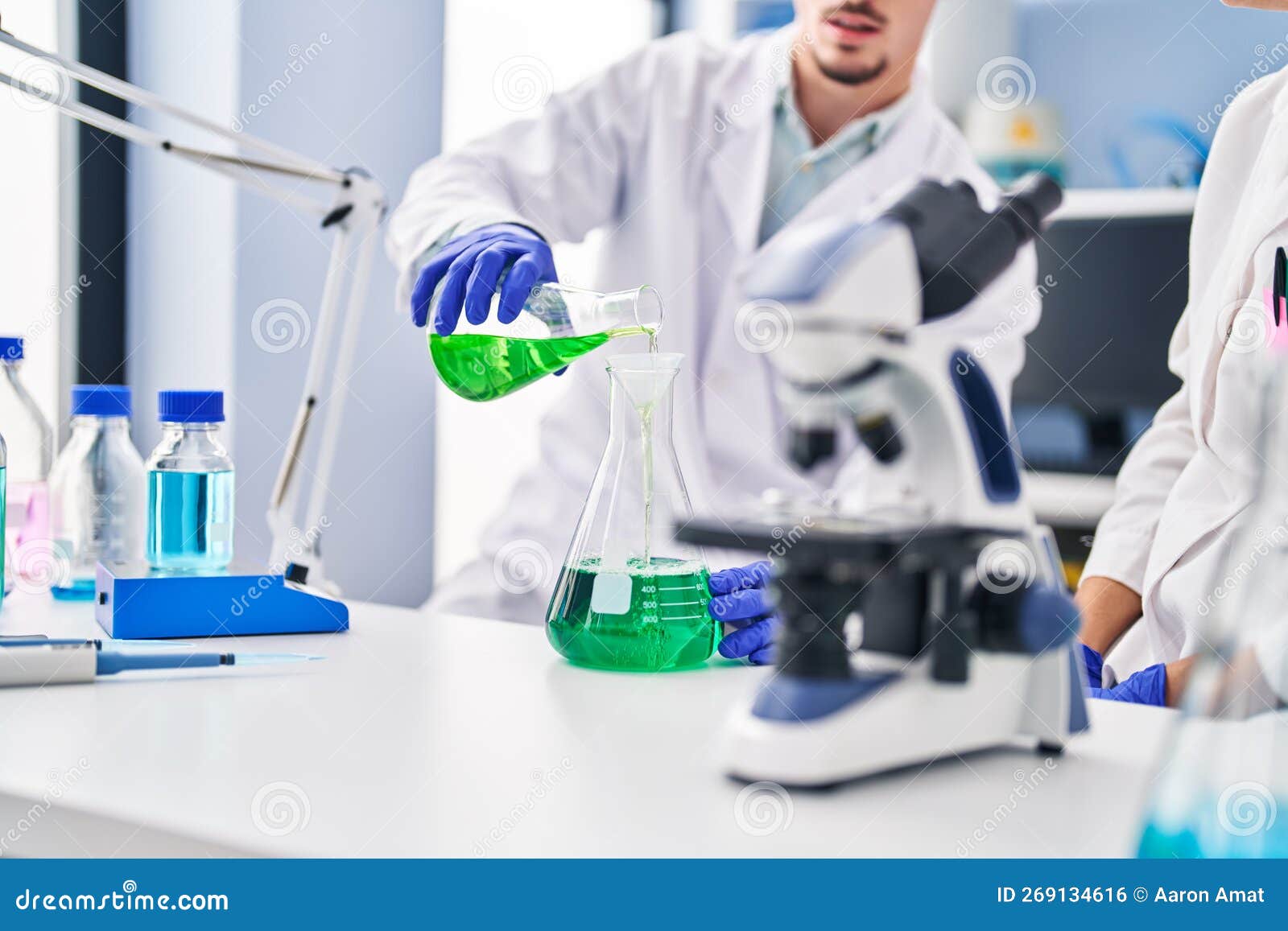 Young Man and Woman Scientists Workers Measuring Liquid at Laboratory ...