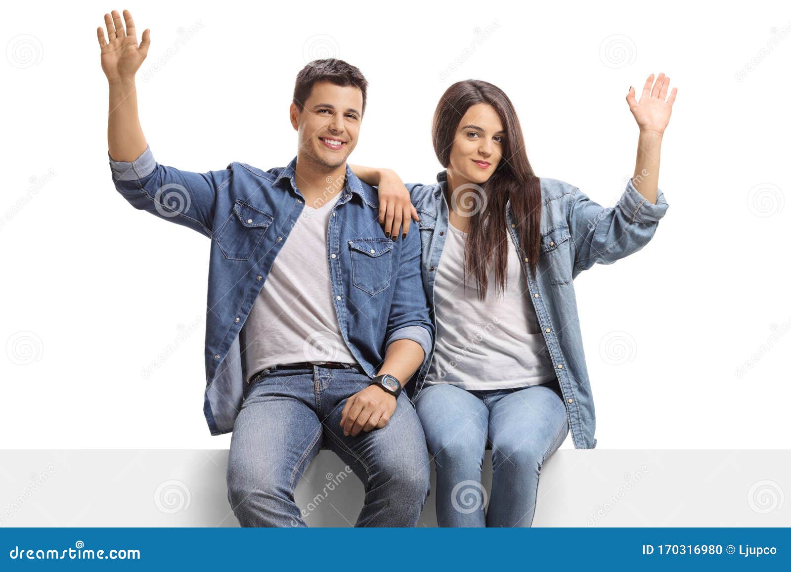 Young Man And Woman Sitting On A Panel And Waving At The Camera Stock