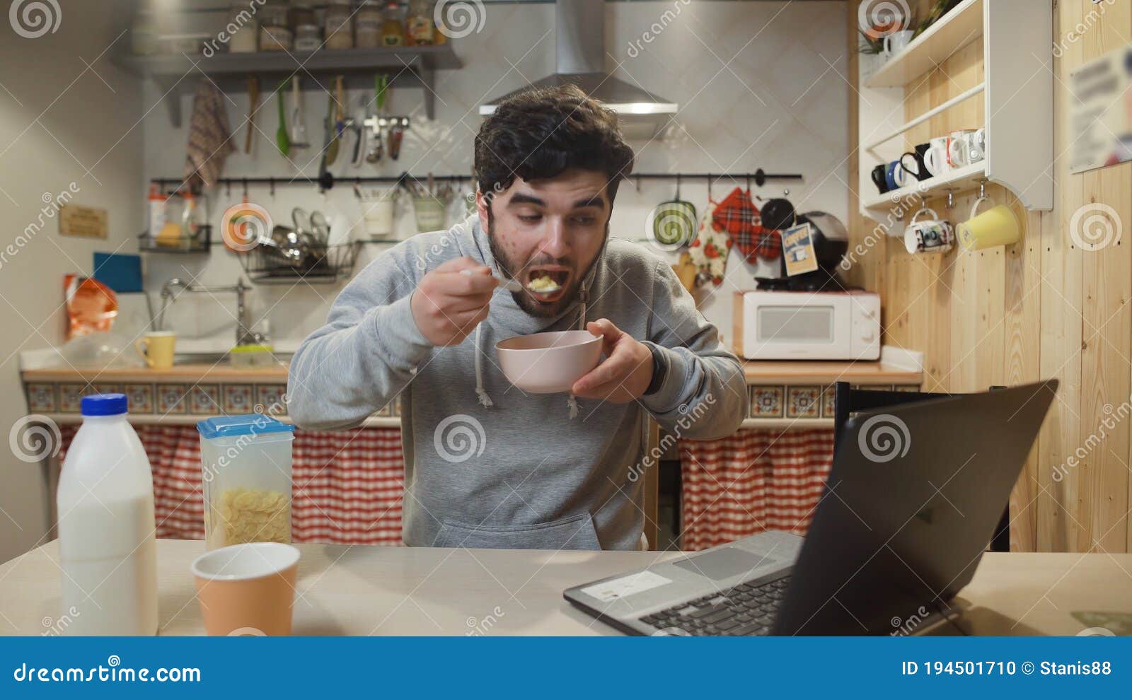 Young Man Working Laptop Computer and Eats Corn Flakes Cereal at Home ...