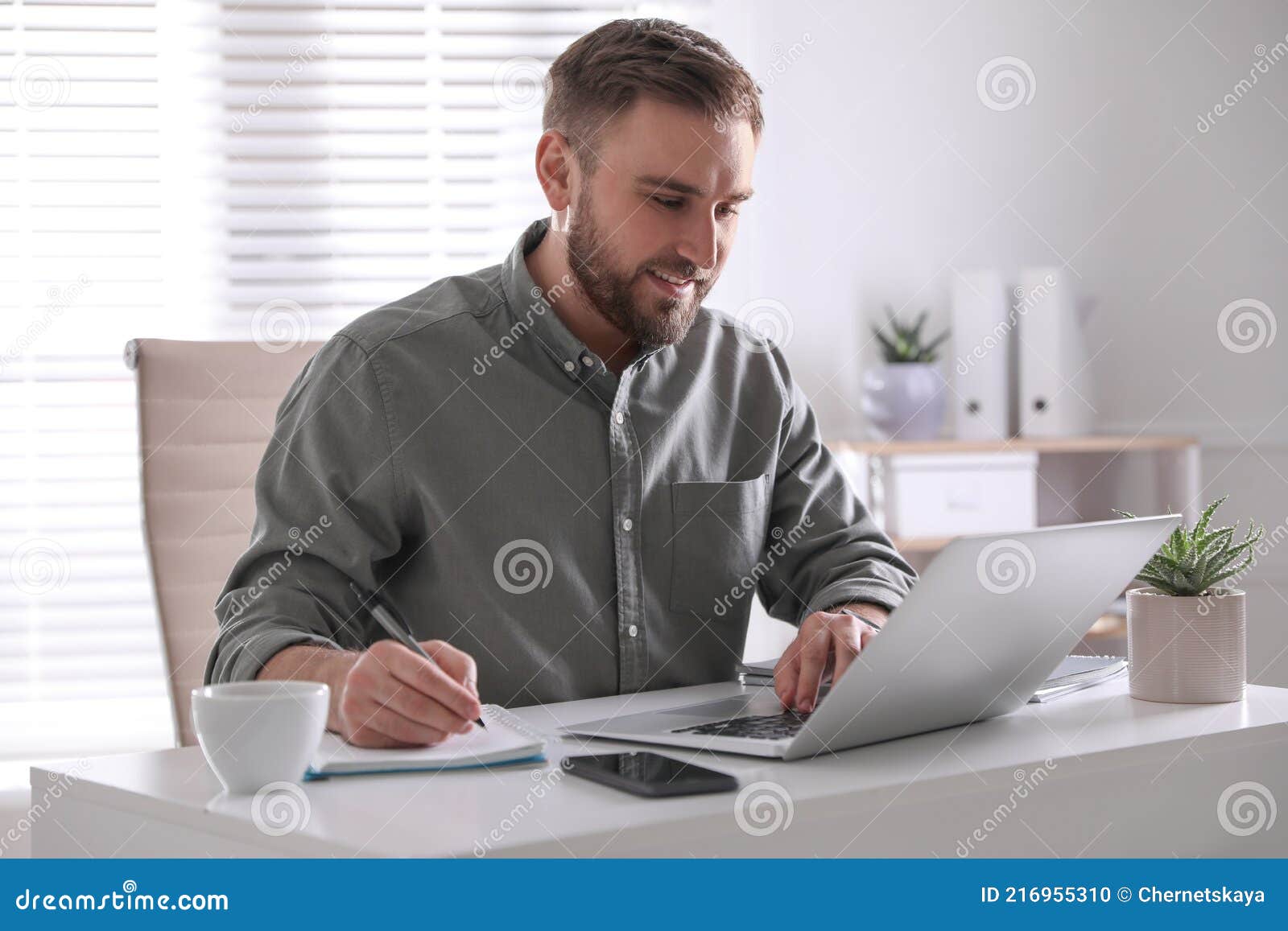Young Man Working on Laptop at Table in Office Stock Photo - Image of ...