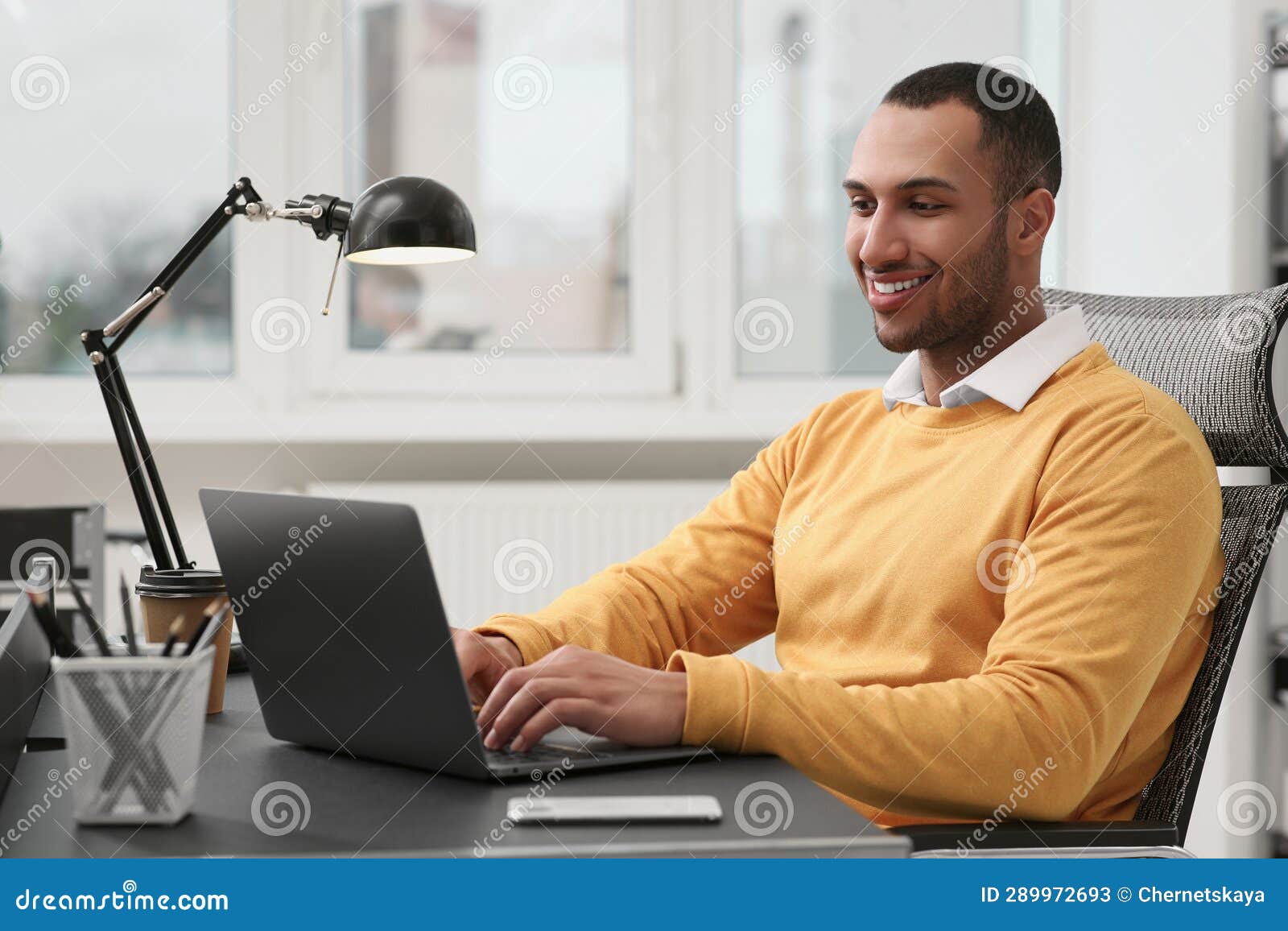 Young Man Working on Laptop at Table in Office Stock Image - Image of ...