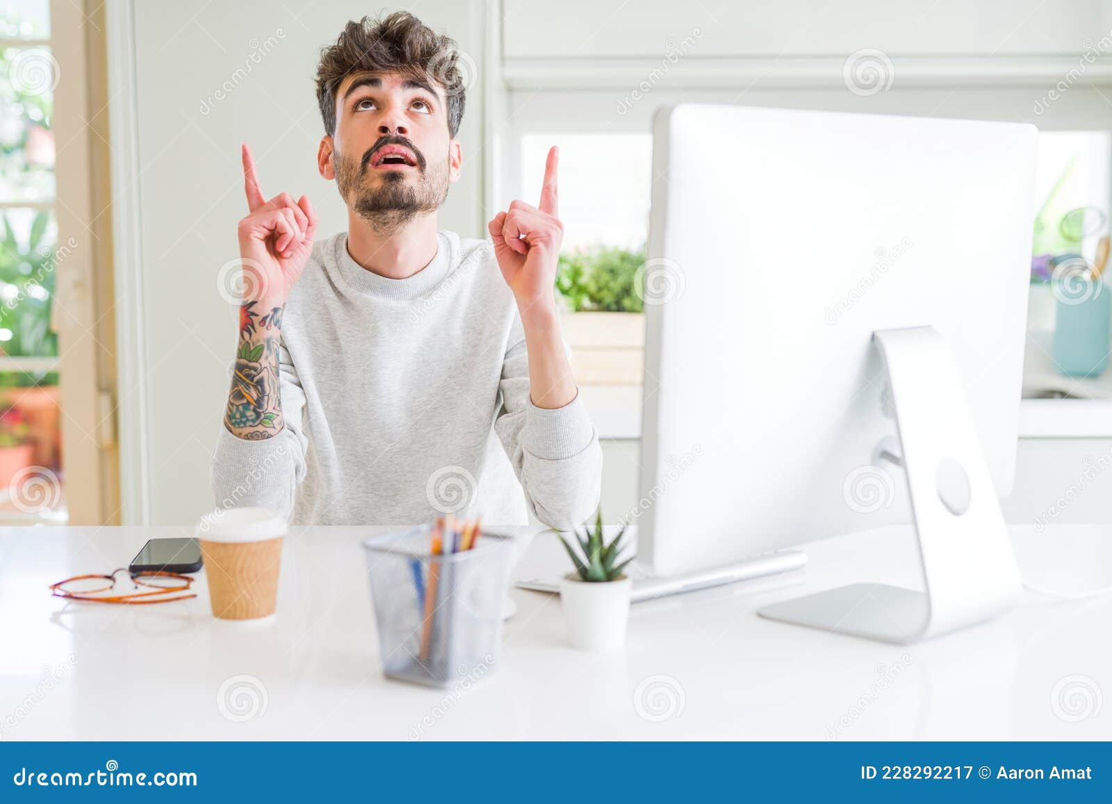 Young Man Working Using Computer Amazed and Surprised Looking Up and ...