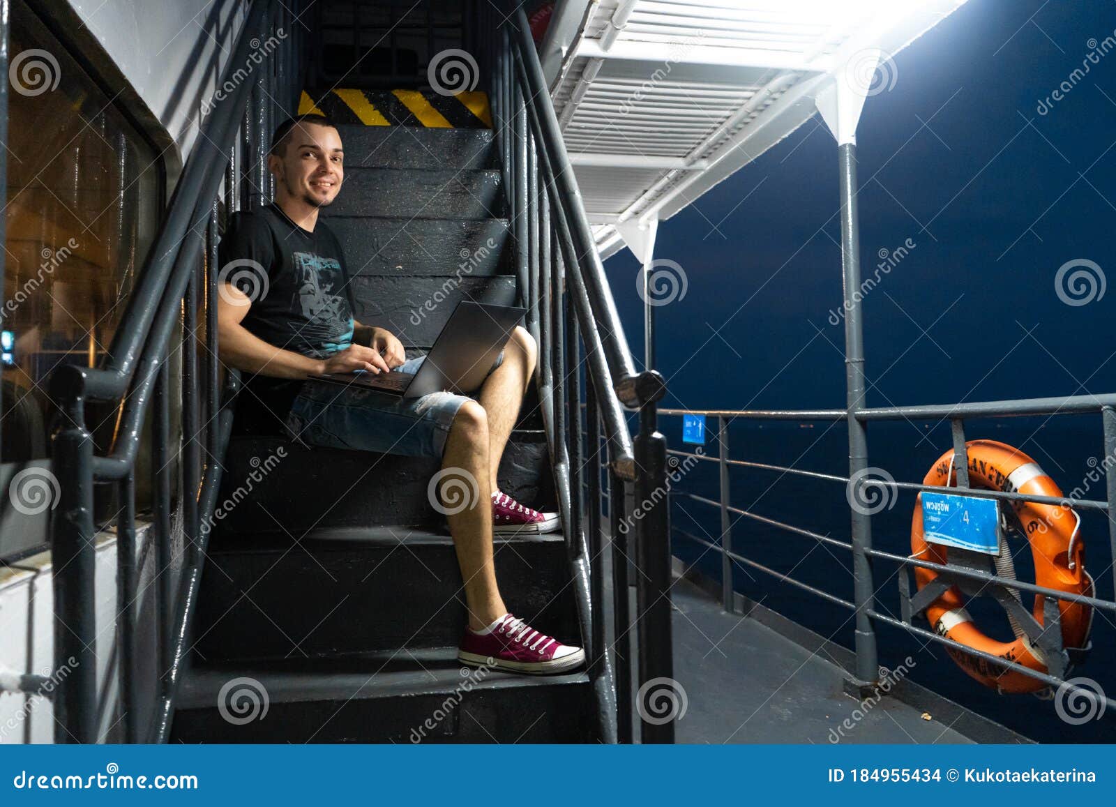 A Young Man Works on a Laptop on the Deck of a Ship. Remote Work Stock ...