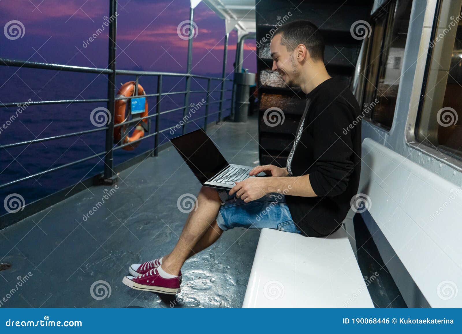 A Young Man Works on a Laptop on the Deck of a Ship. Remote Work Stock ...