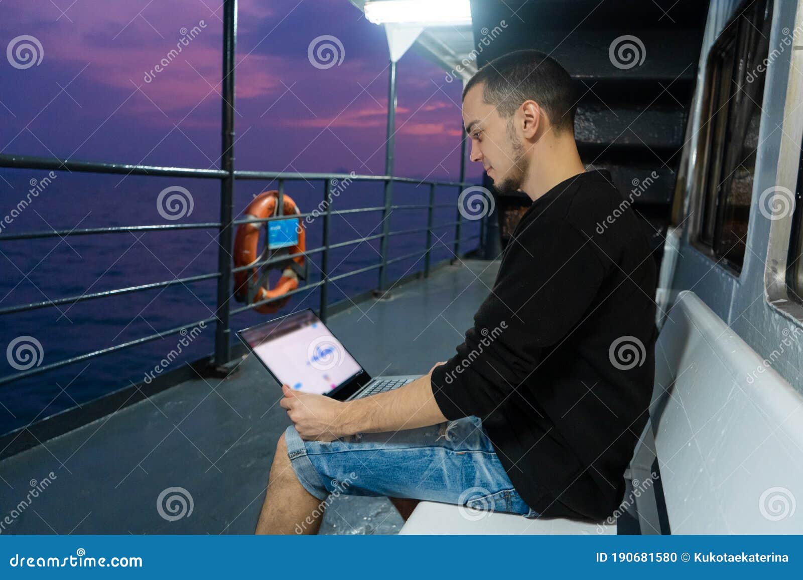A Young Man Works on a Laptop on the Deck of a Ship. Remote Work Stock ...