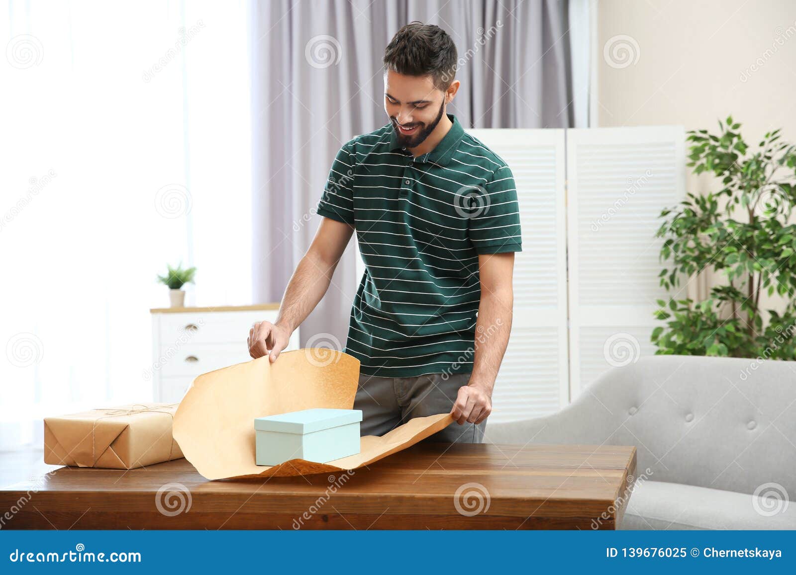Young Man Wrapping Parcel on Table Stock Image - Image of adult, home ...