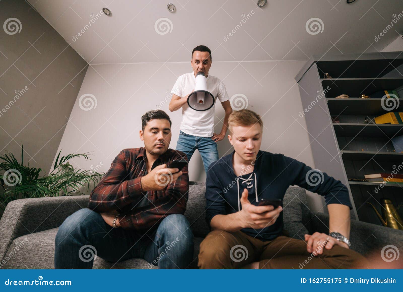 Young Man Yelling through a Loudspeaker at Friends Watching TV. Stock ...