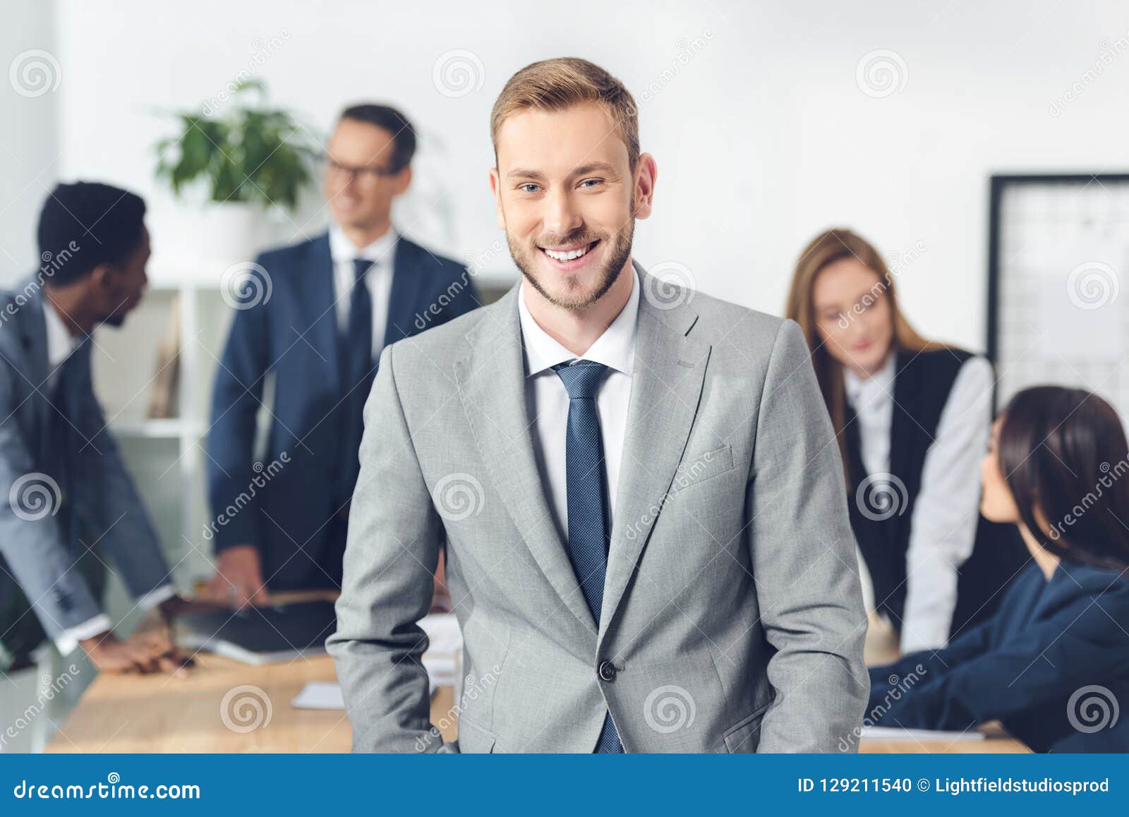 Handsome Young Manager Looking at Camera with Blurred Businesspeople ...