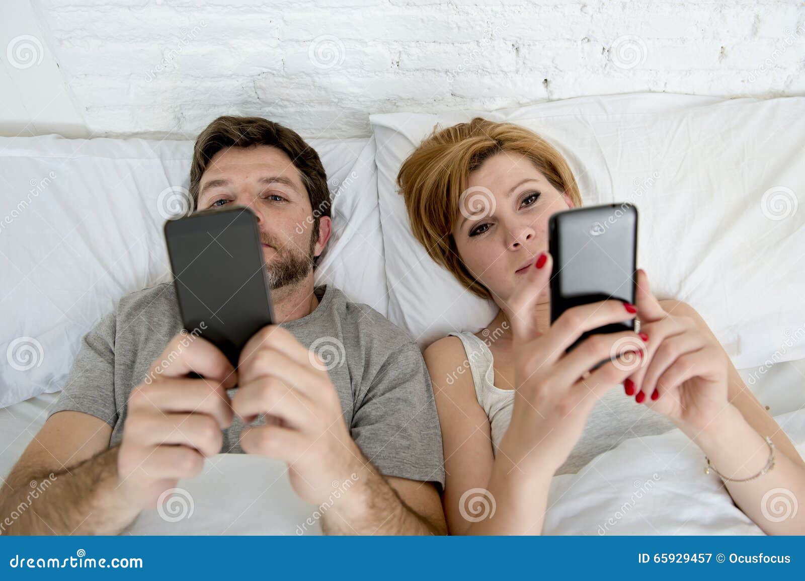 Young Married Couple Using Their Mobile Phone in Bed Ignoring Each ...