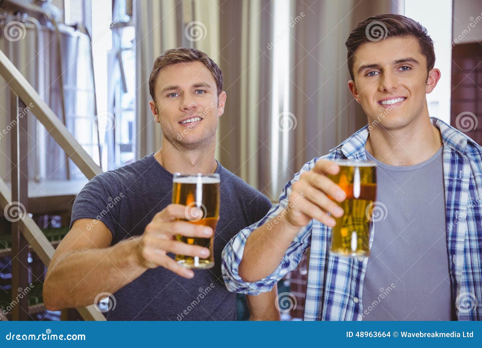 Young Men Holding a Pint of Beer Smiling at Camera Stock Photo - Image ...