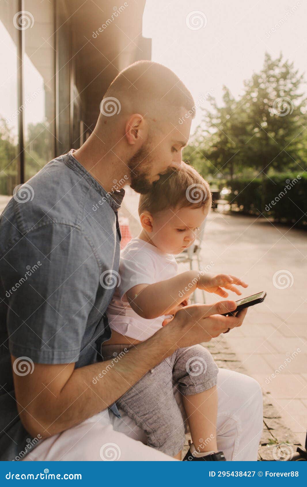 Young Man Using a Phone Mobile for Work and Holding His Son on His Hand ...