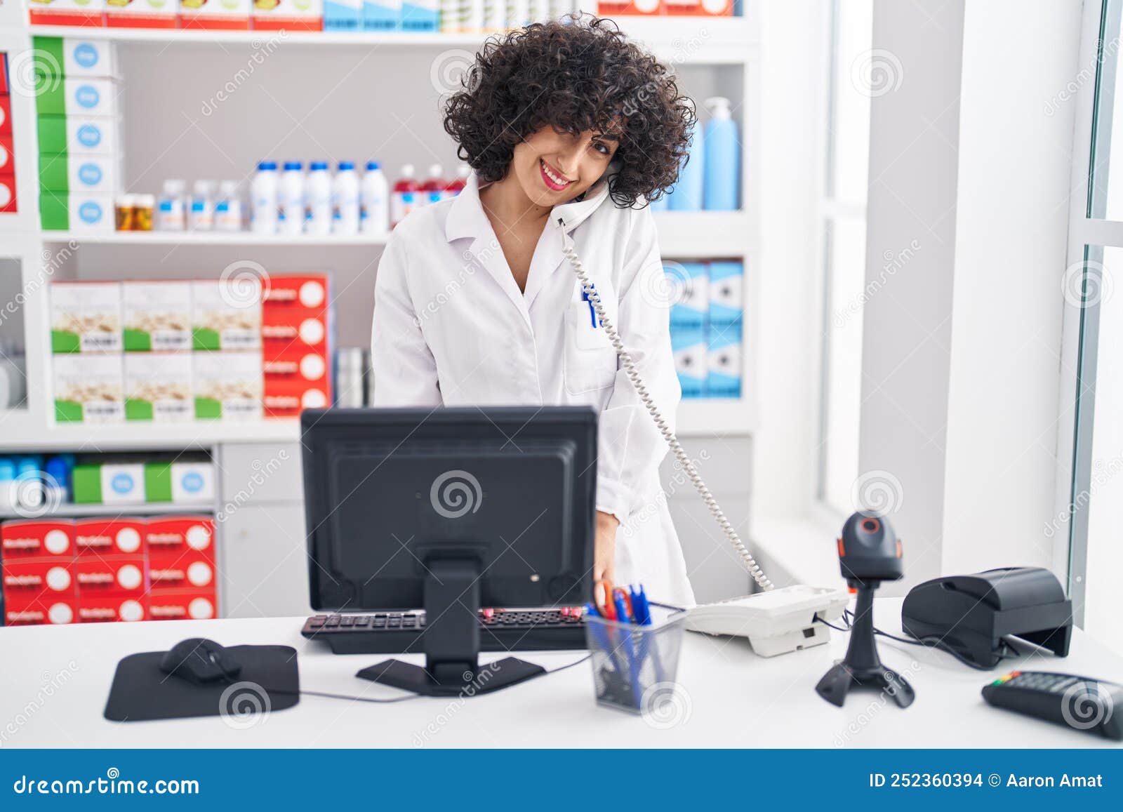 Young Middle East Woman Pharmacist Using Computer Talking on Telephone ...