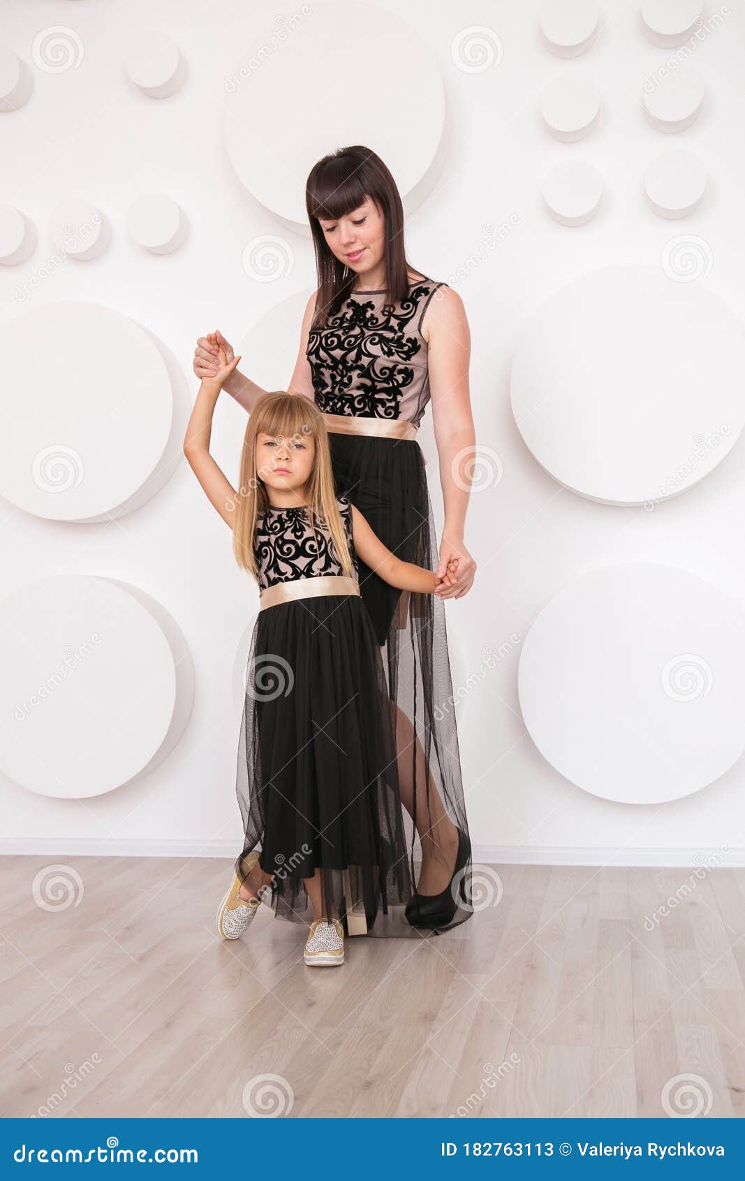 Young Mother With Daughter In Identical Dresses On White Background