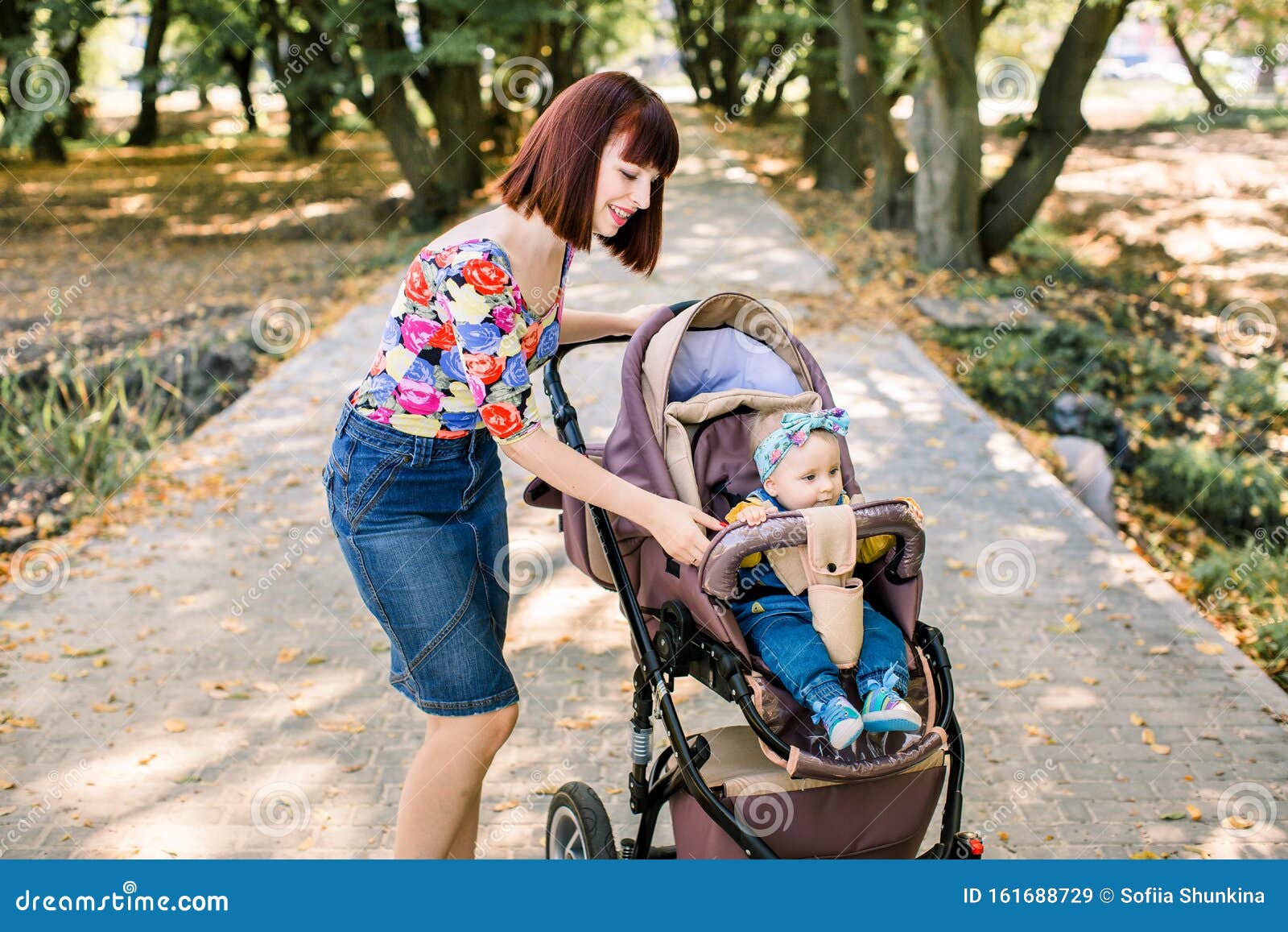 Young Mother Looking at Her Child in a Baby Stroller Stock Image ...