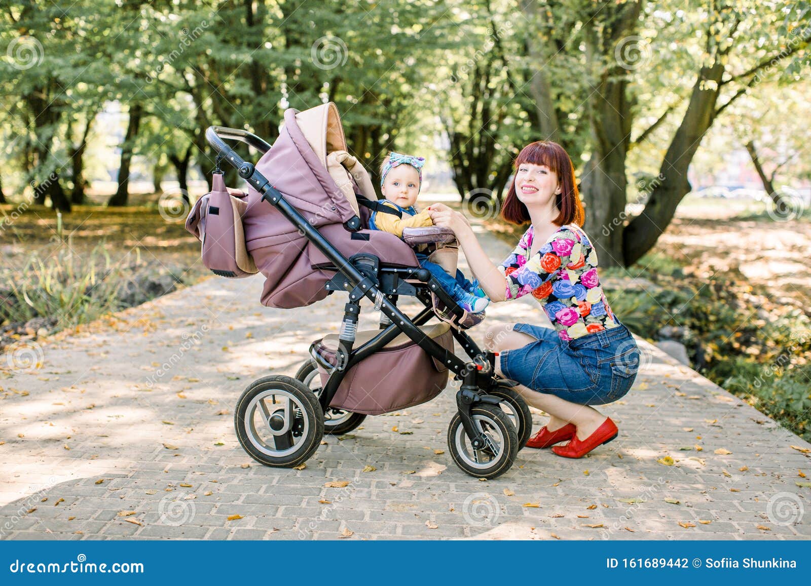 Young Mother Looking at Her Child in a Baby Stroller Stock Photo ...
