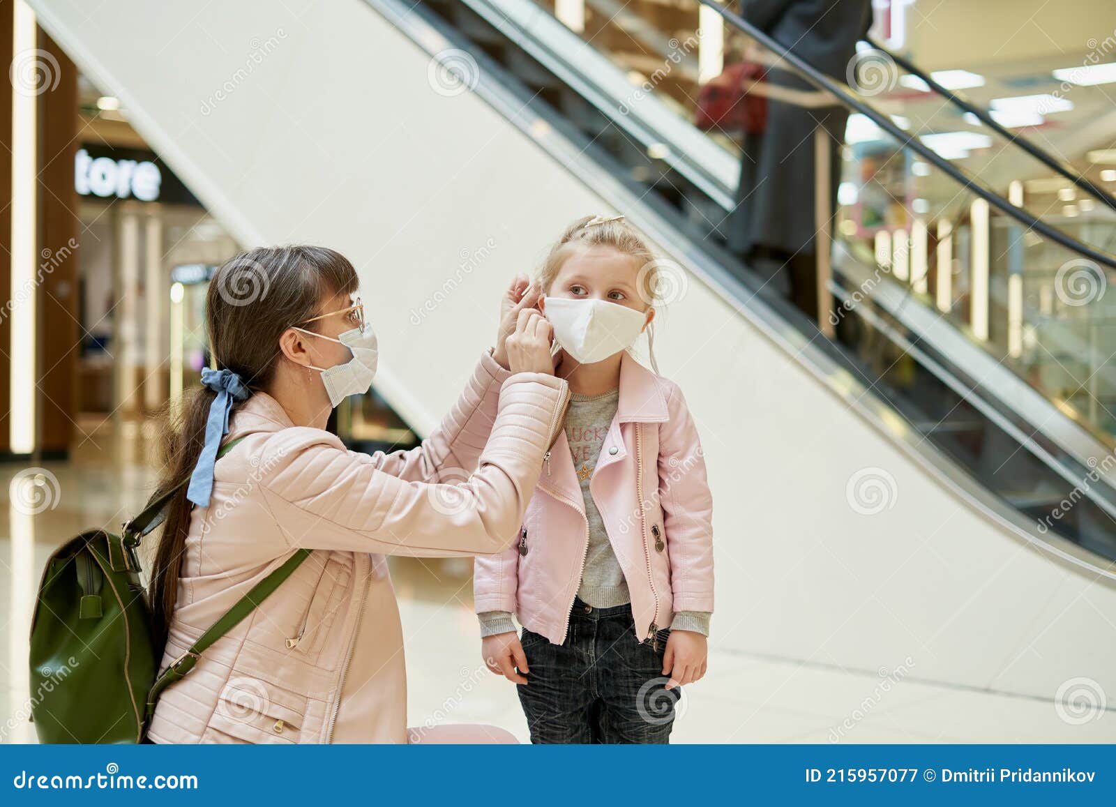 Young Mother Puts a Protective Mask on Her Daughter in the Mall Stock ...