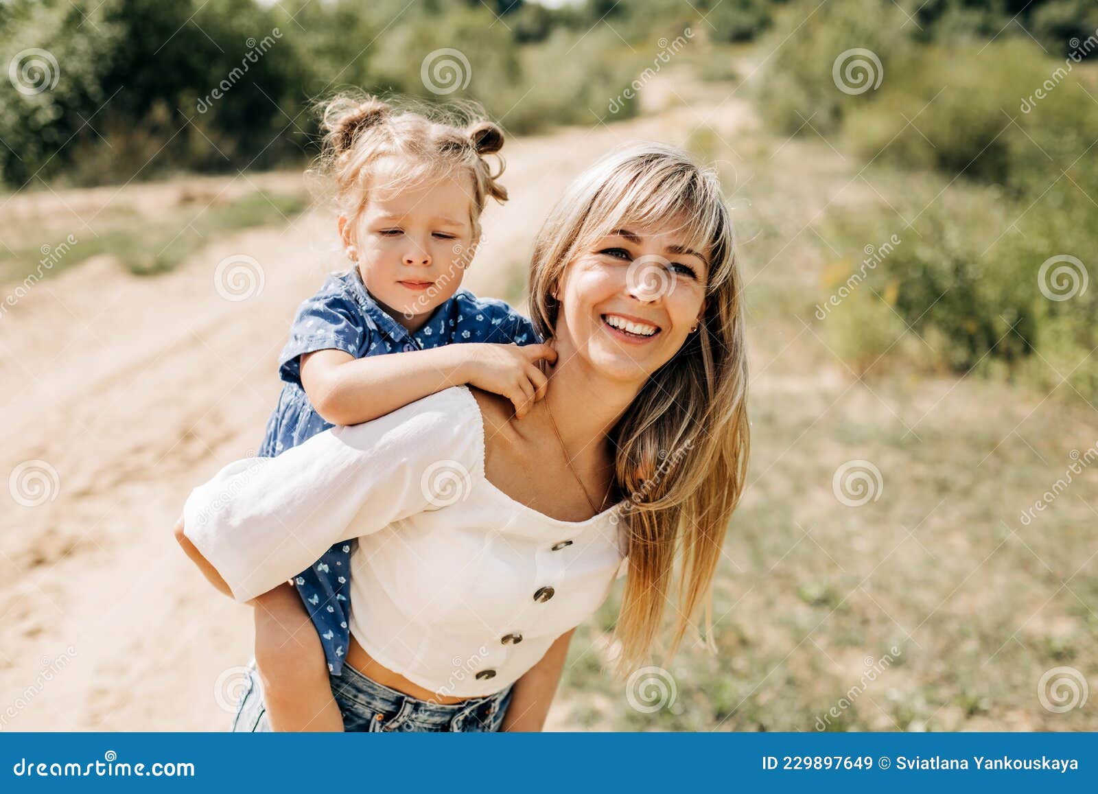 A Young Mother Rolls Her Little Daughter on Her Back, the Baby Hugs Her ... A Young Mother Rolls Her Little Daughter on Her Back, the Baby Hugs Her ...