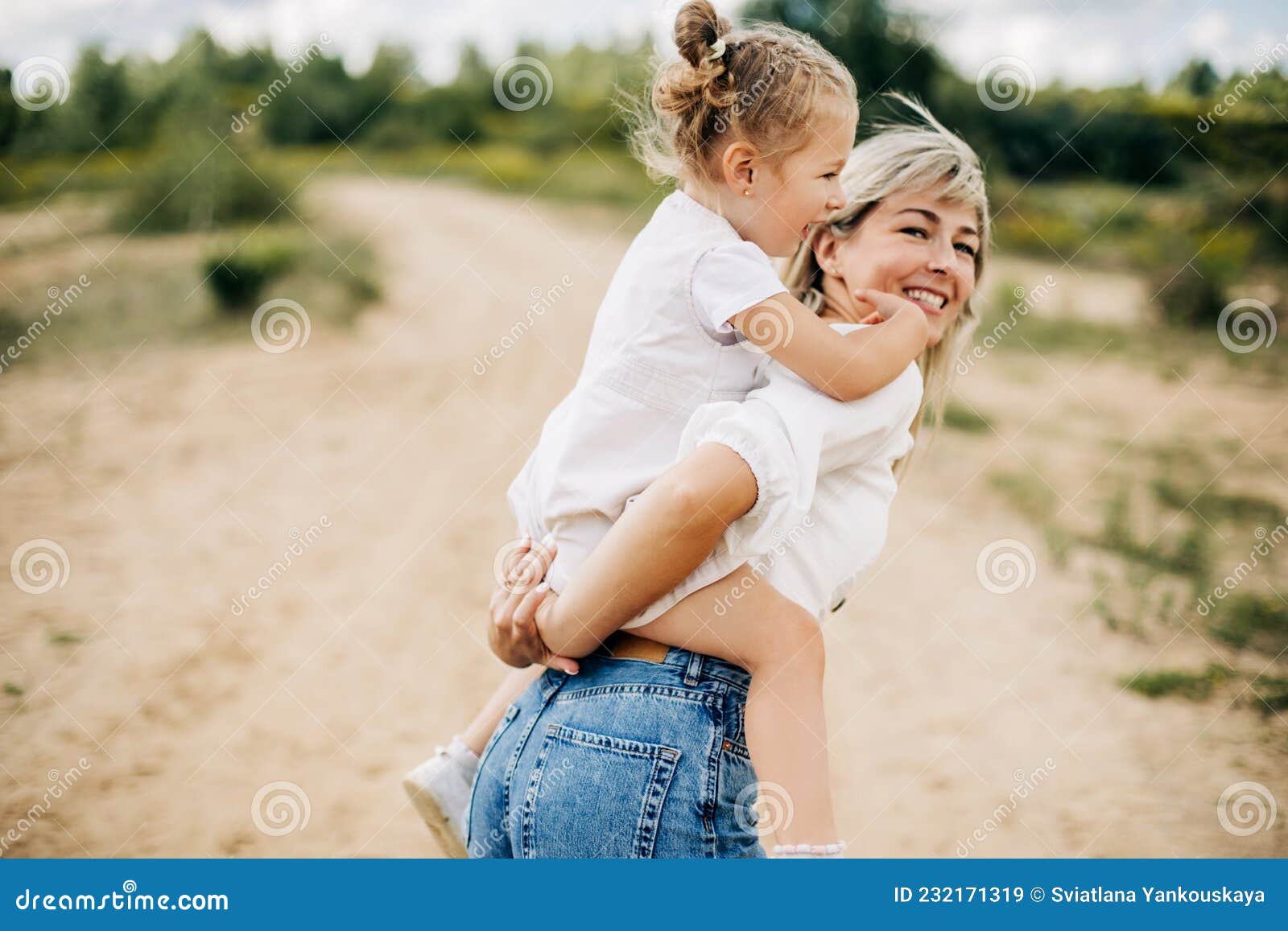 A Young Mother Rolls Her Little Daughter on Her Back, the Baby Hugs Her ... A Young Mother Rolls Her Little Daughter on Her Back, the Baby Hugs Her ...