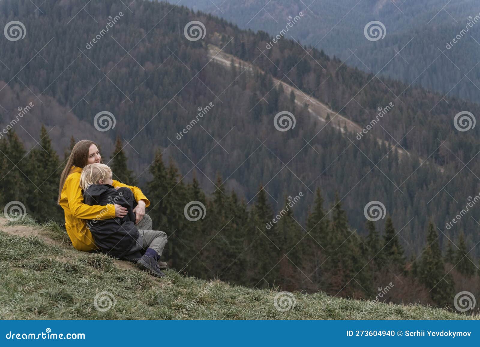 Young Mother with Son Sit on Hillside. Mother and Son Rest and Sit in ...