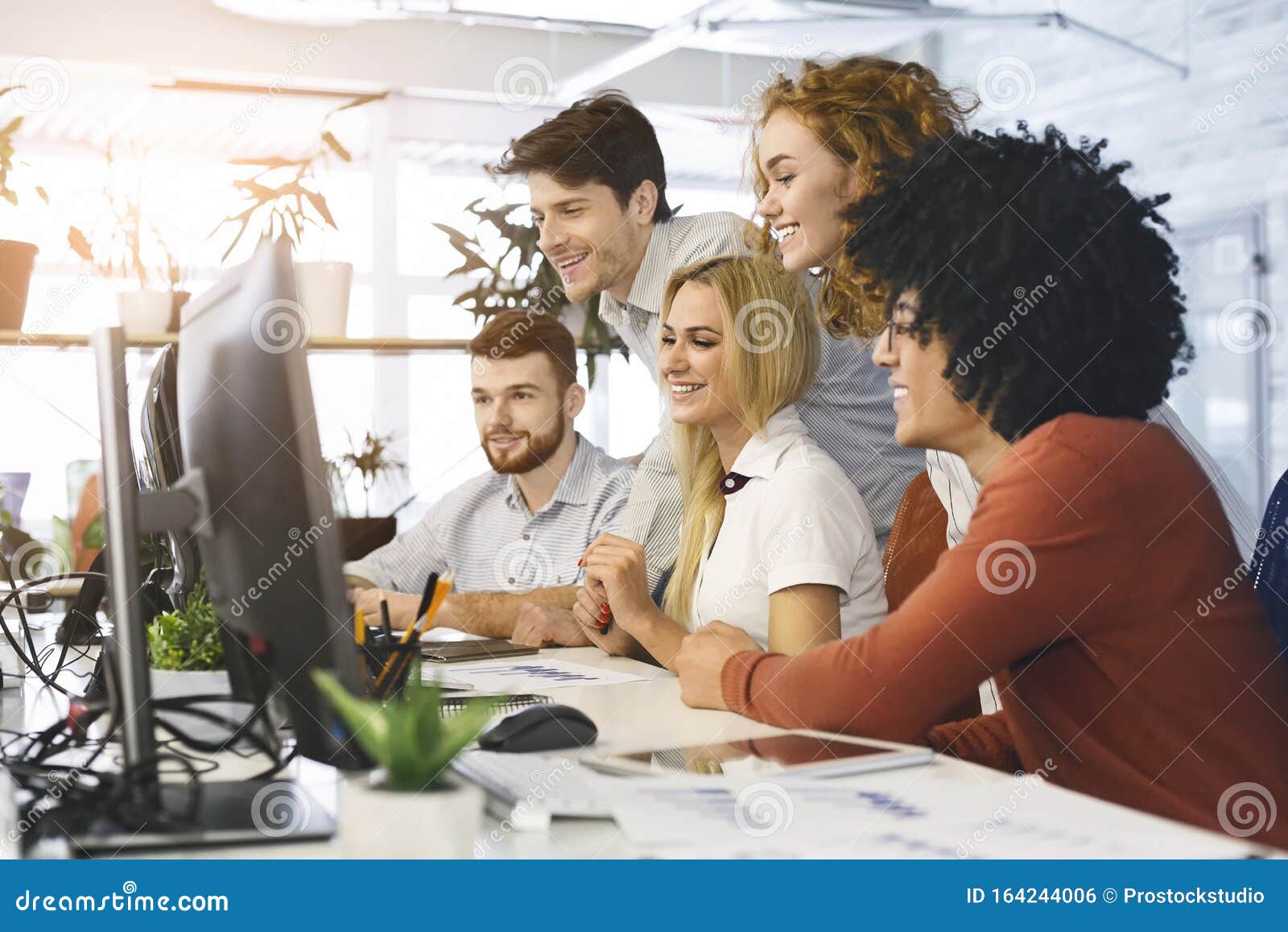 Young Motivated Team Looking at Computer Screen in Office Together ...