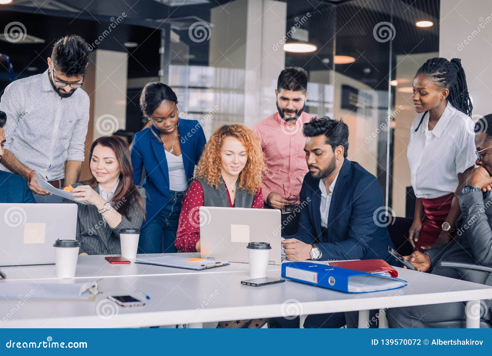Young Multi-ethnic Work Team Exchanges Ideas Gathering Around Laptop ...