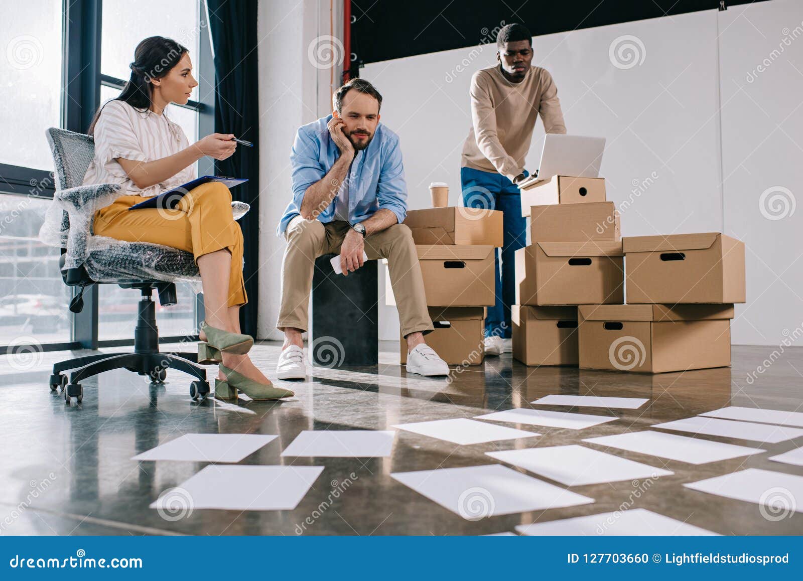 Young Multiethnic Business People Looking at Papers on Floor in New ... Young Multiethnic Business People Looking at Papers on Floor in New ...