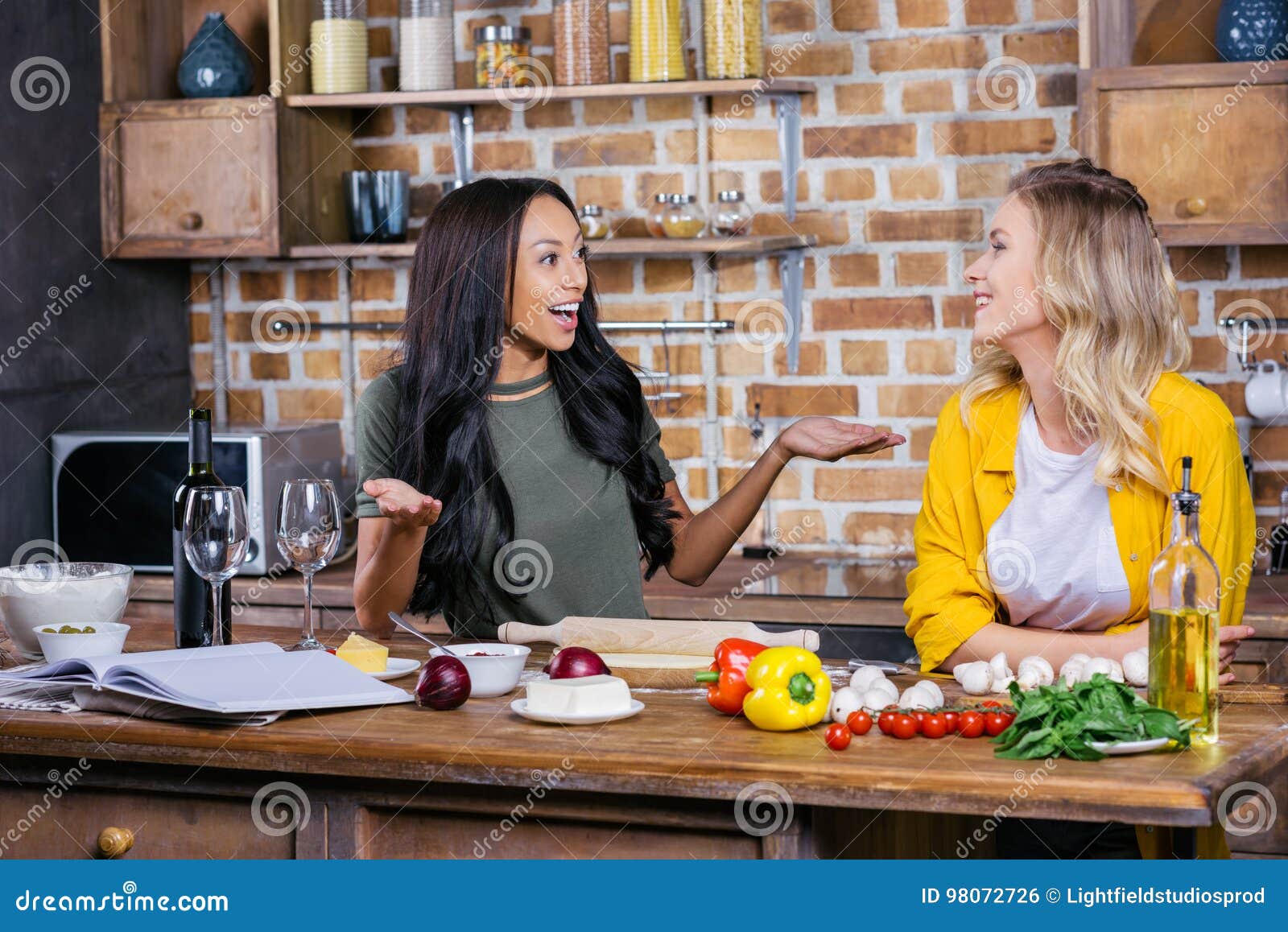 Young Multiethnic Women Cooking Together and Talking in Kitchen Stock ...