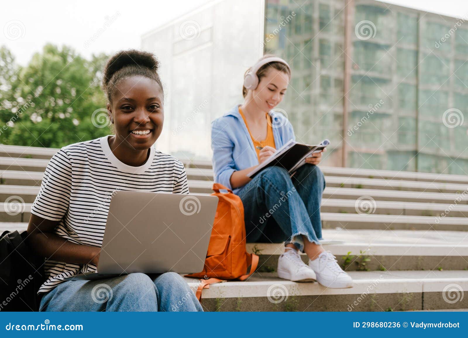 Young Multiracial Student Women Doing Homework while Sitting on Stairs ...