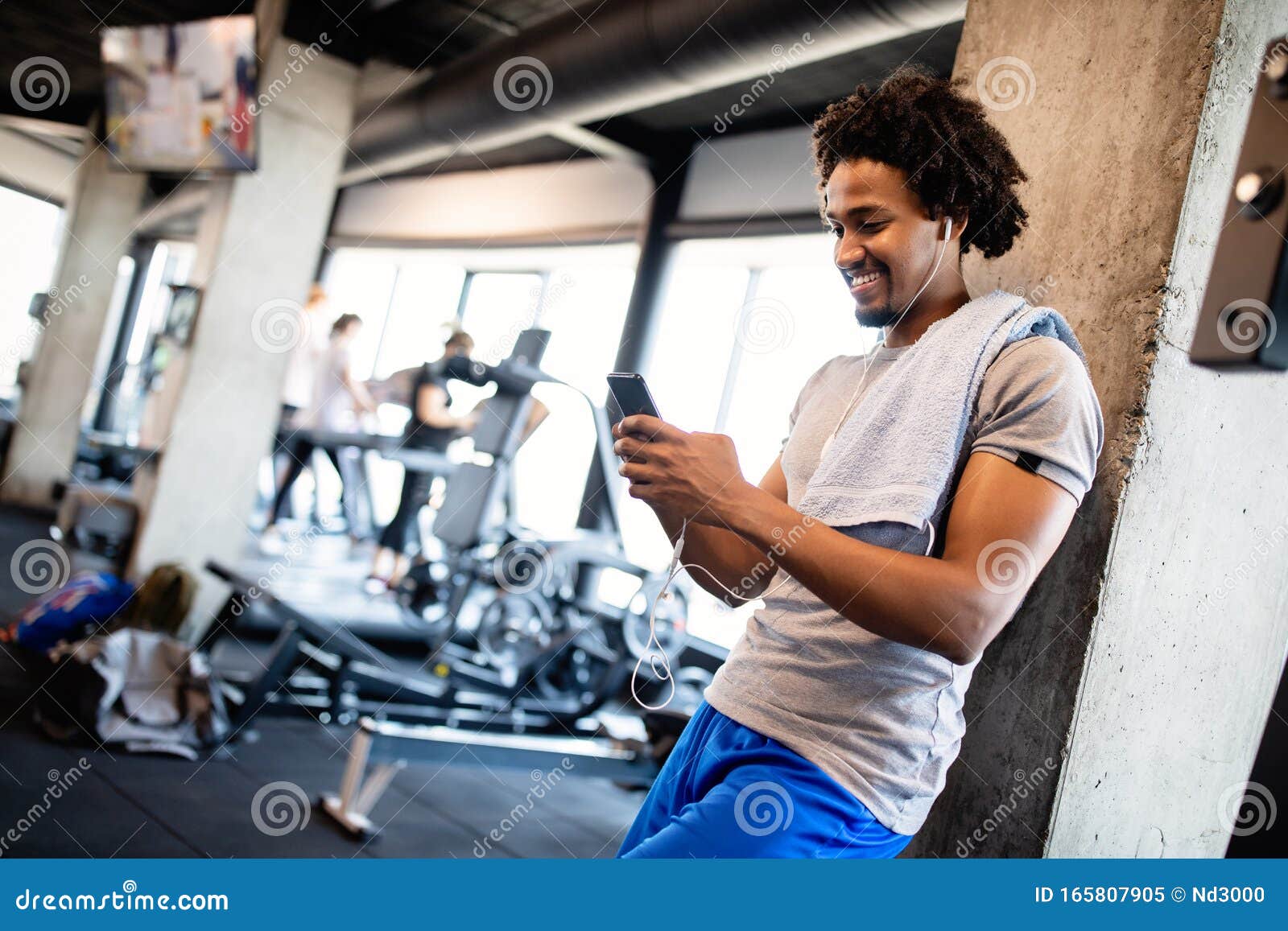 Young Muscular Man Using Mobile Phone at the Gym in Exercise Break ...
