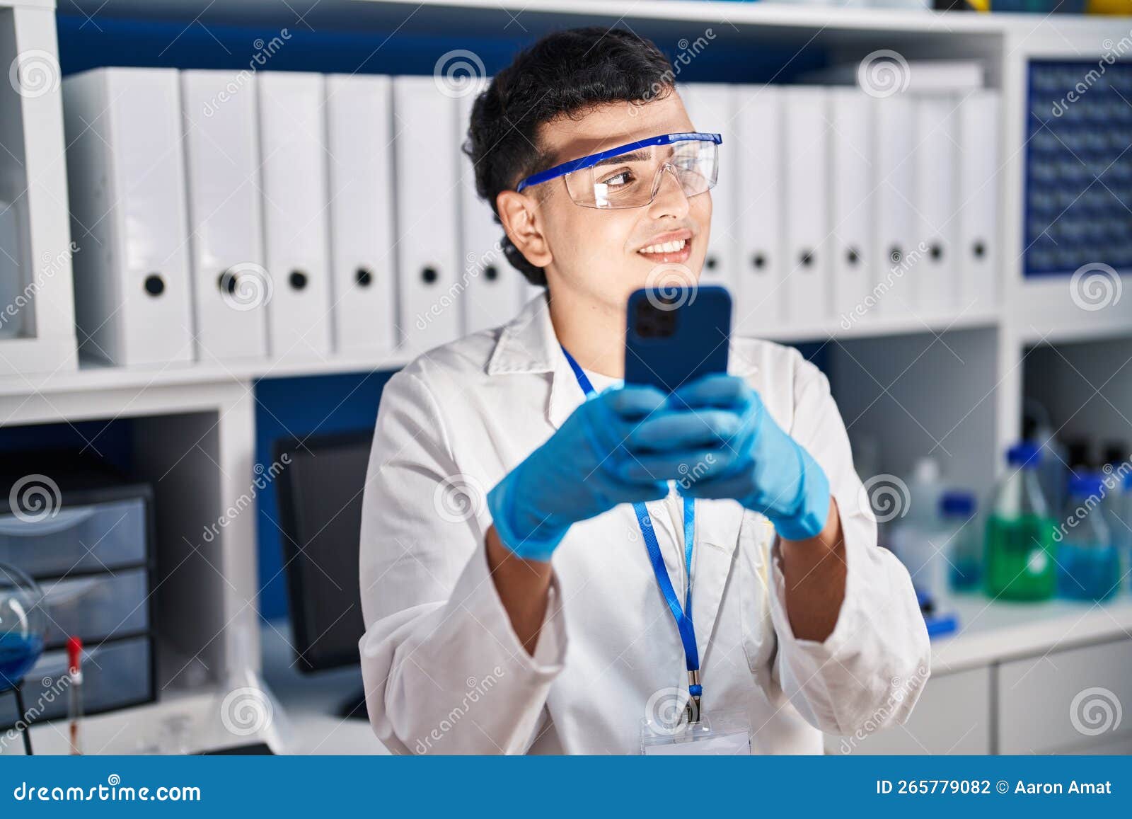 Young Non Binary Man Scientist Smiling Confident Using Smartphone at ...