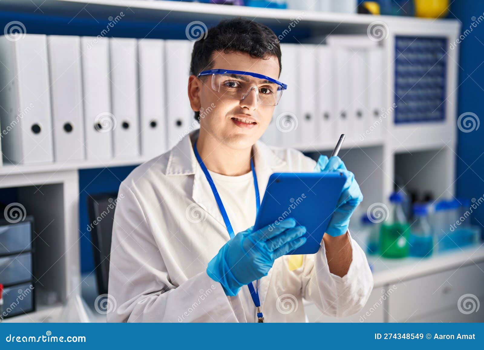 Young Non Binary Man Scientist Smiling Confident Write on Touchpad at ...