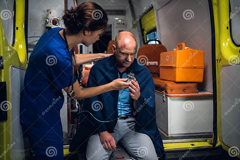 Young Nurse In Uniform Stands With Oxygen Mask And Man Sits In Oxygen