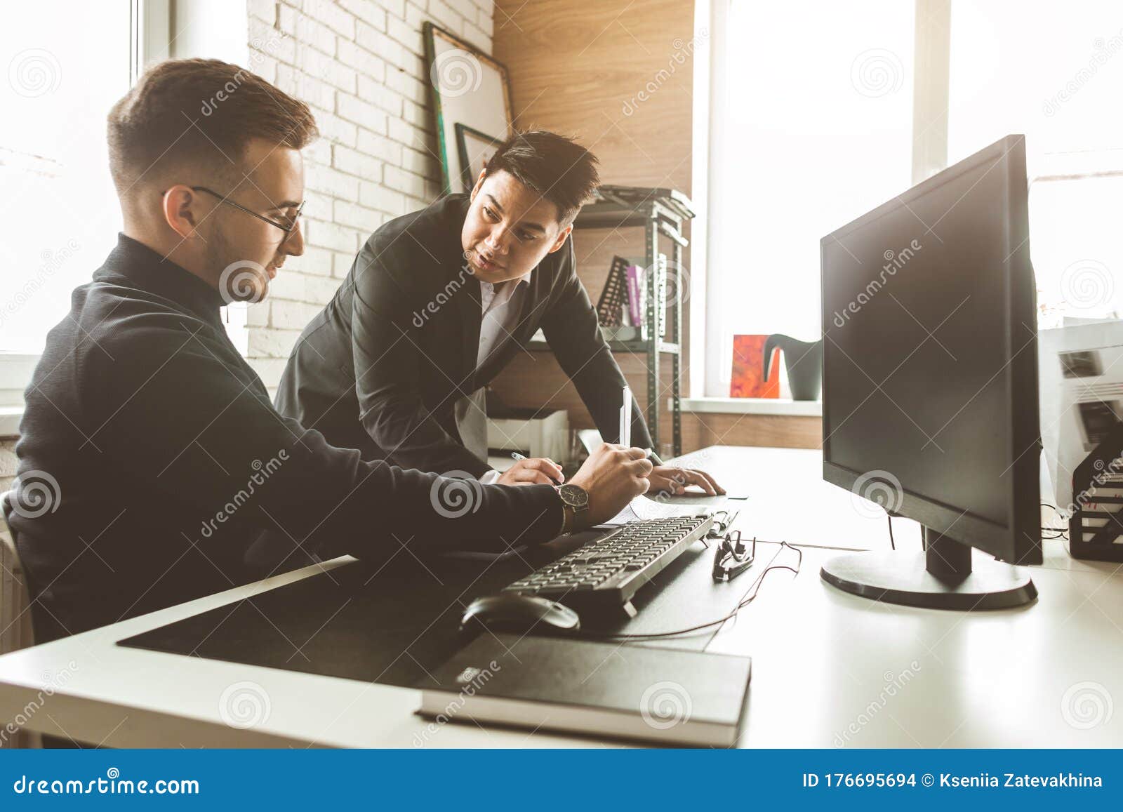 Young Office Worker Sitting at Desk, Using Computer. Two Business Man ...
