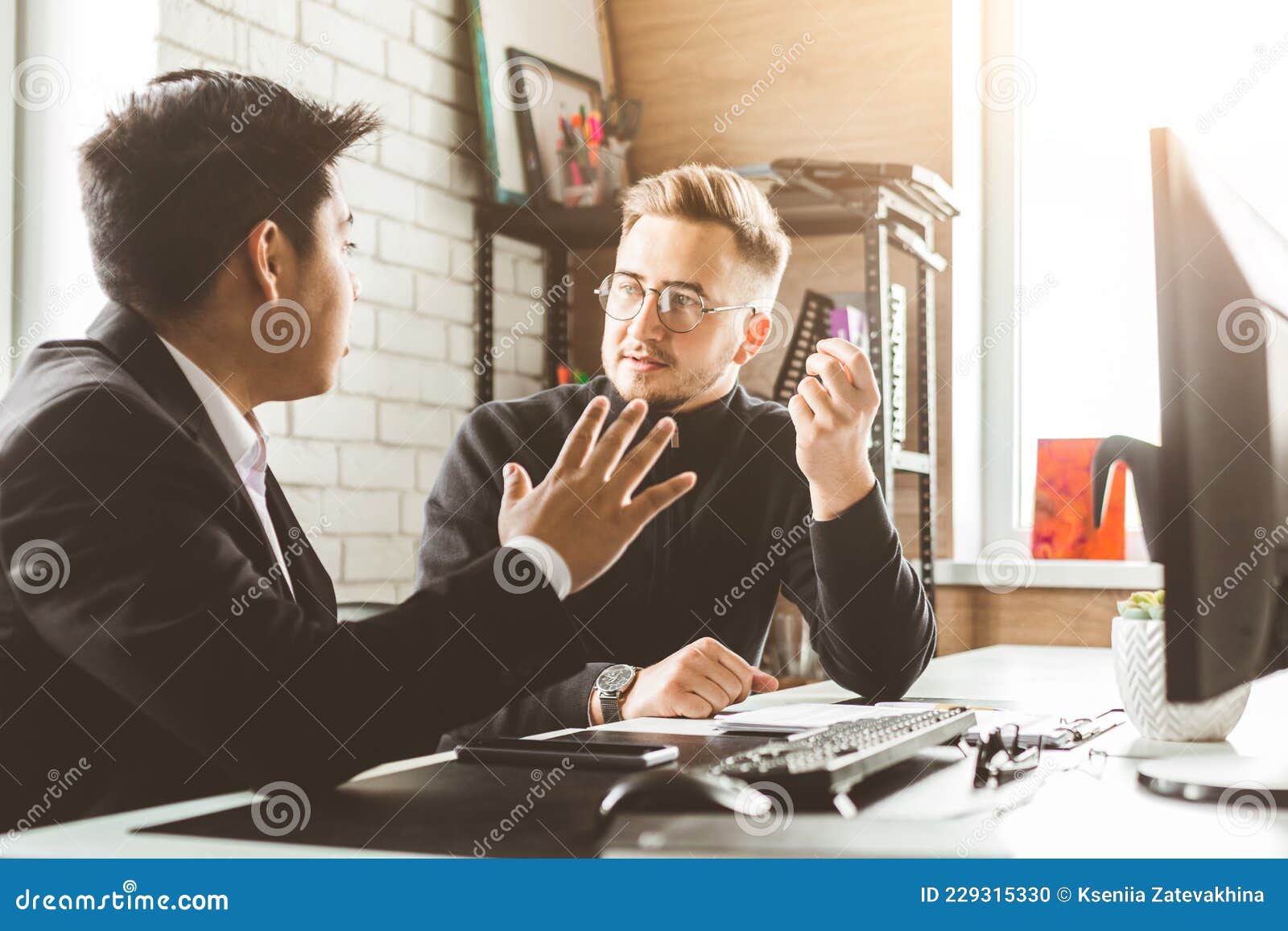 Young Office Worker Sitting at Desk, Using Computer. Two Business Man ...