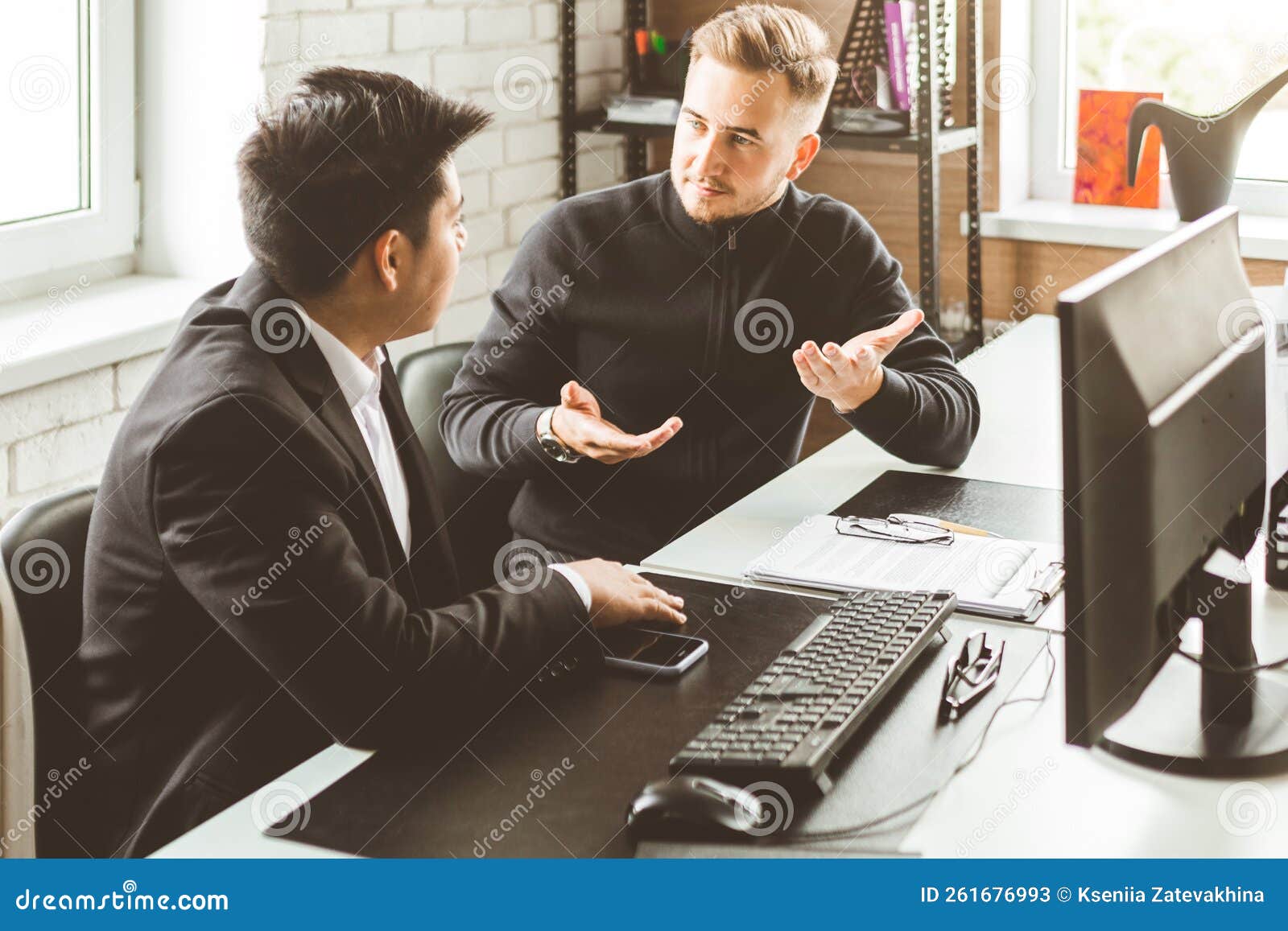 Young Office Worker Sitting at Desk, Using Computer. Two Business Man ...
