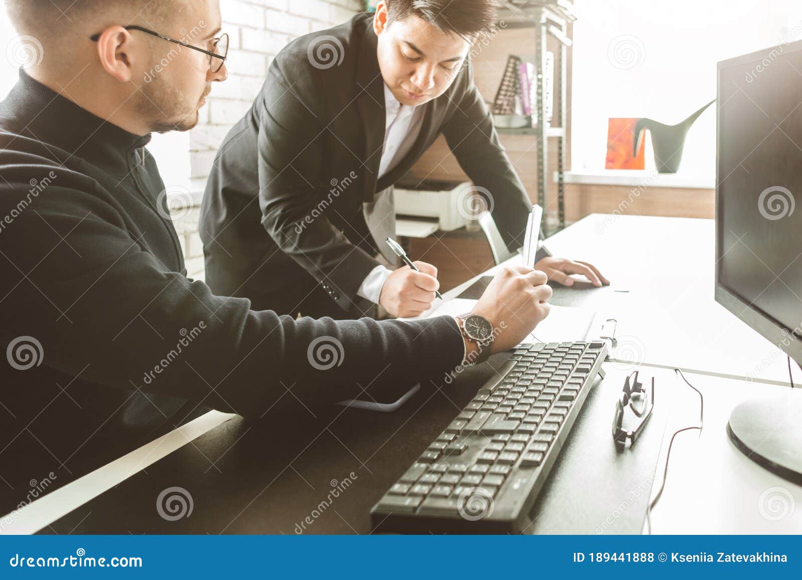 Young Office Worker Sitting at Desk, Using Computer. Two Business Man ...