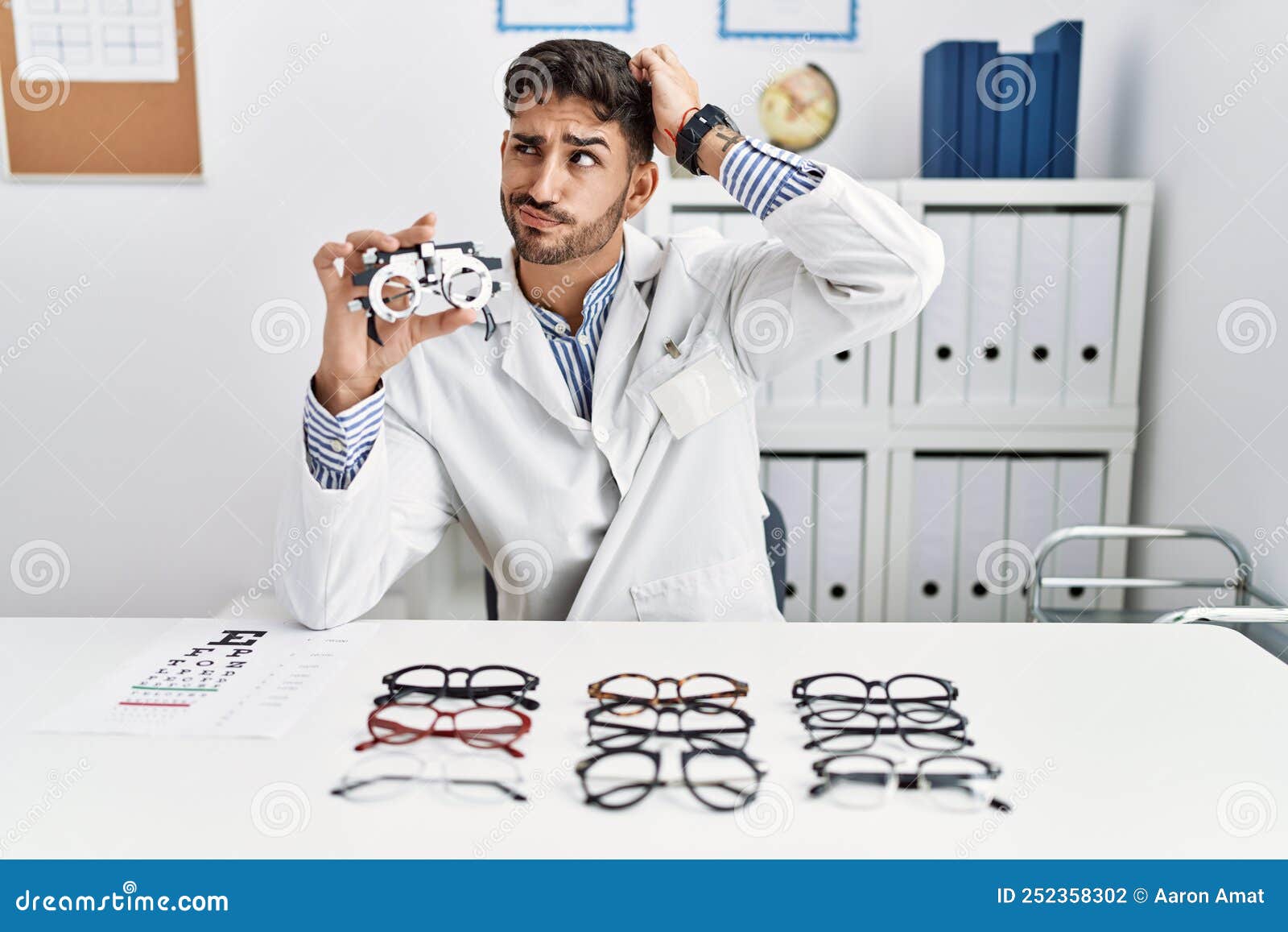 Young Optician Man Holding Optometry Glasses Confuse and Wondering ...
