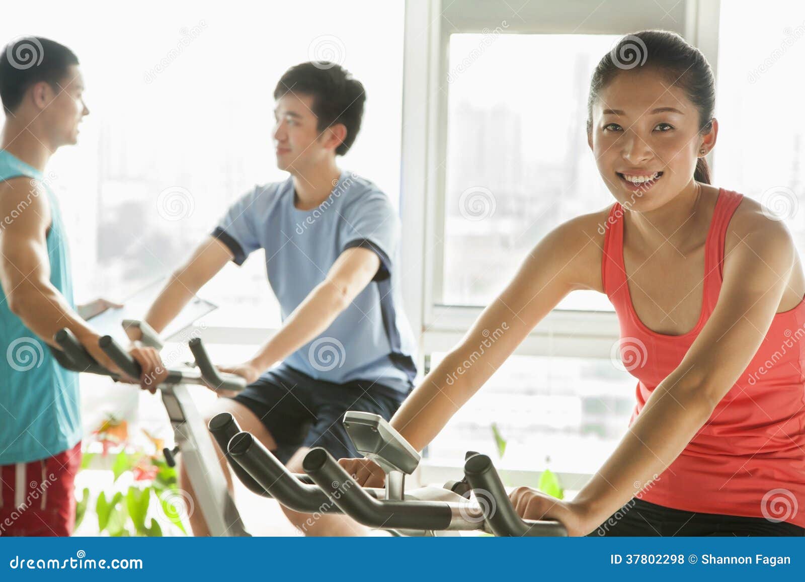 Young People on Stationary Bikes Exercising in the Gym Stock Photo ...